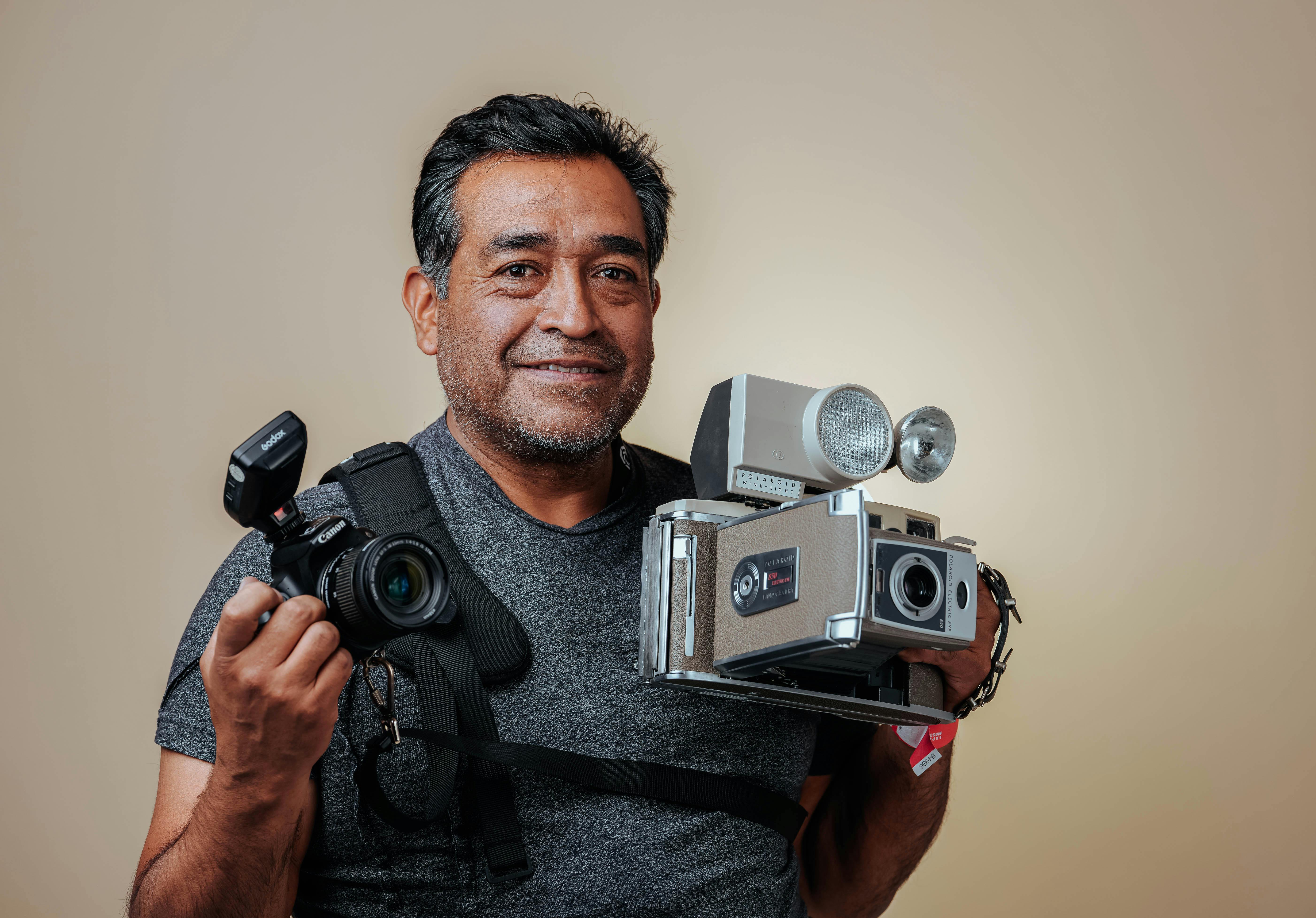 A Smiling Man Holding Two Cameras · Free Stock Photo