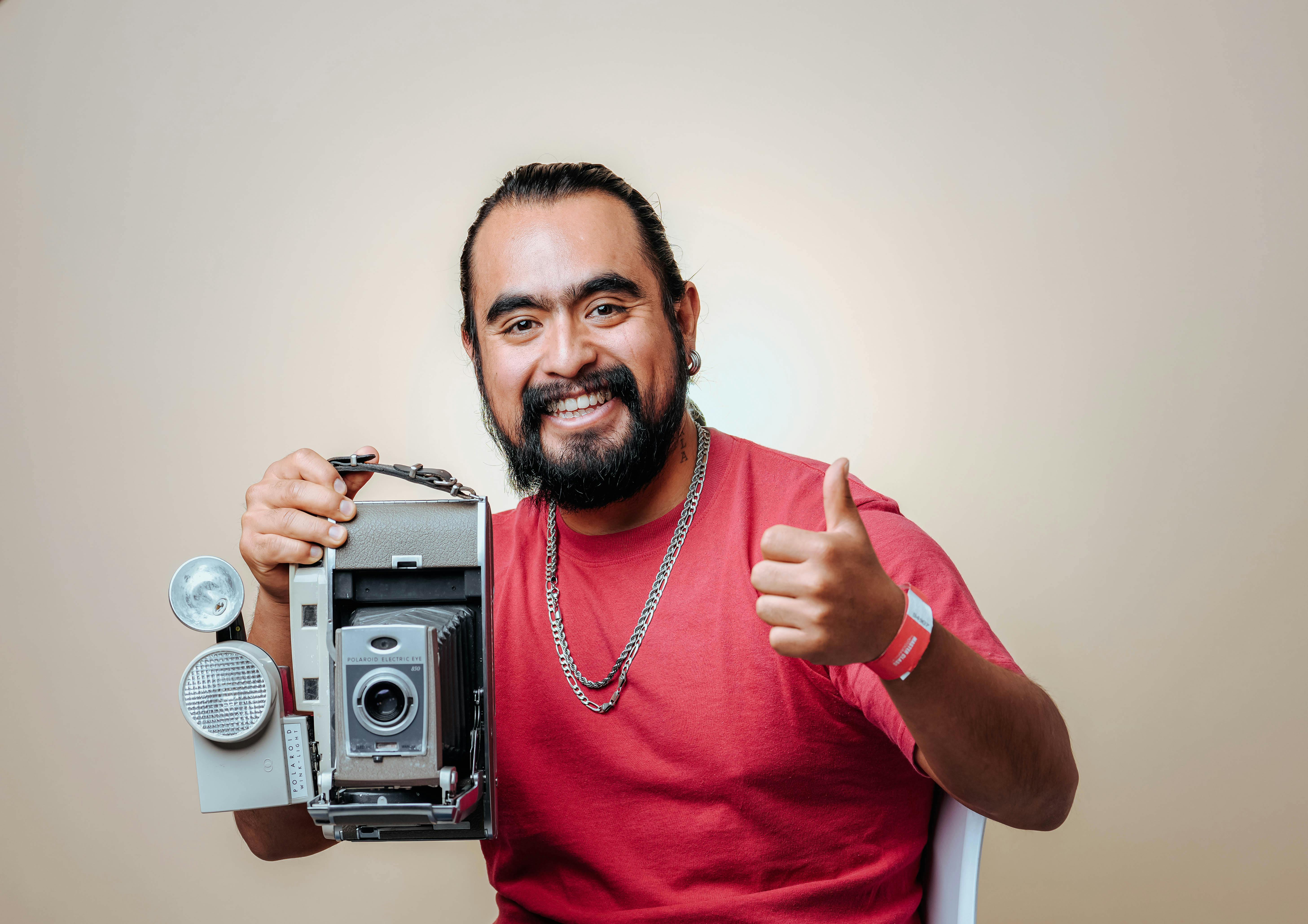 Man Holding a Camera and Making a Thumbs Up Gesture · Free Stock Photo