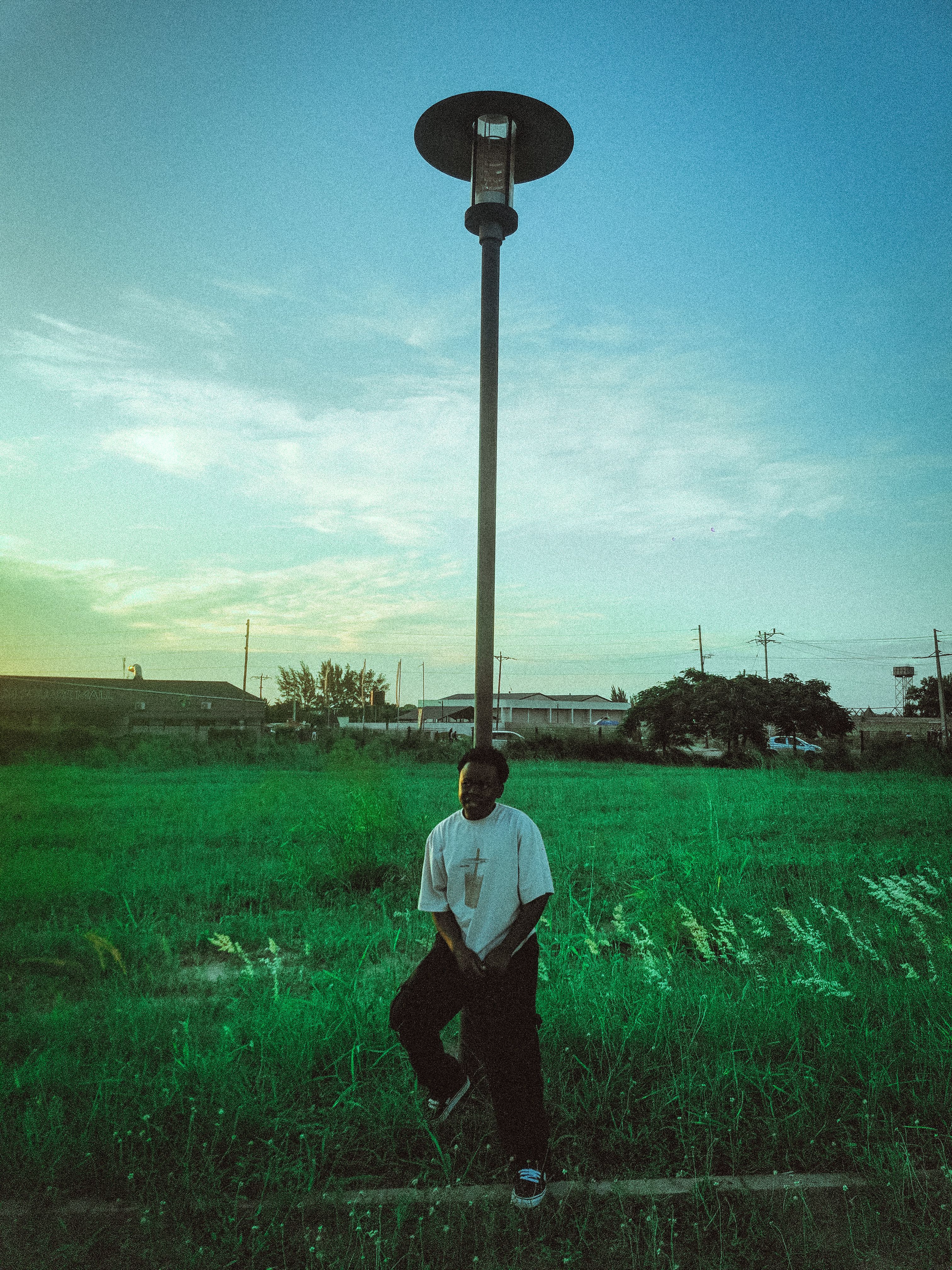 Boy Leaning against a Lamp Post in a Meadow · Free Stock Photo