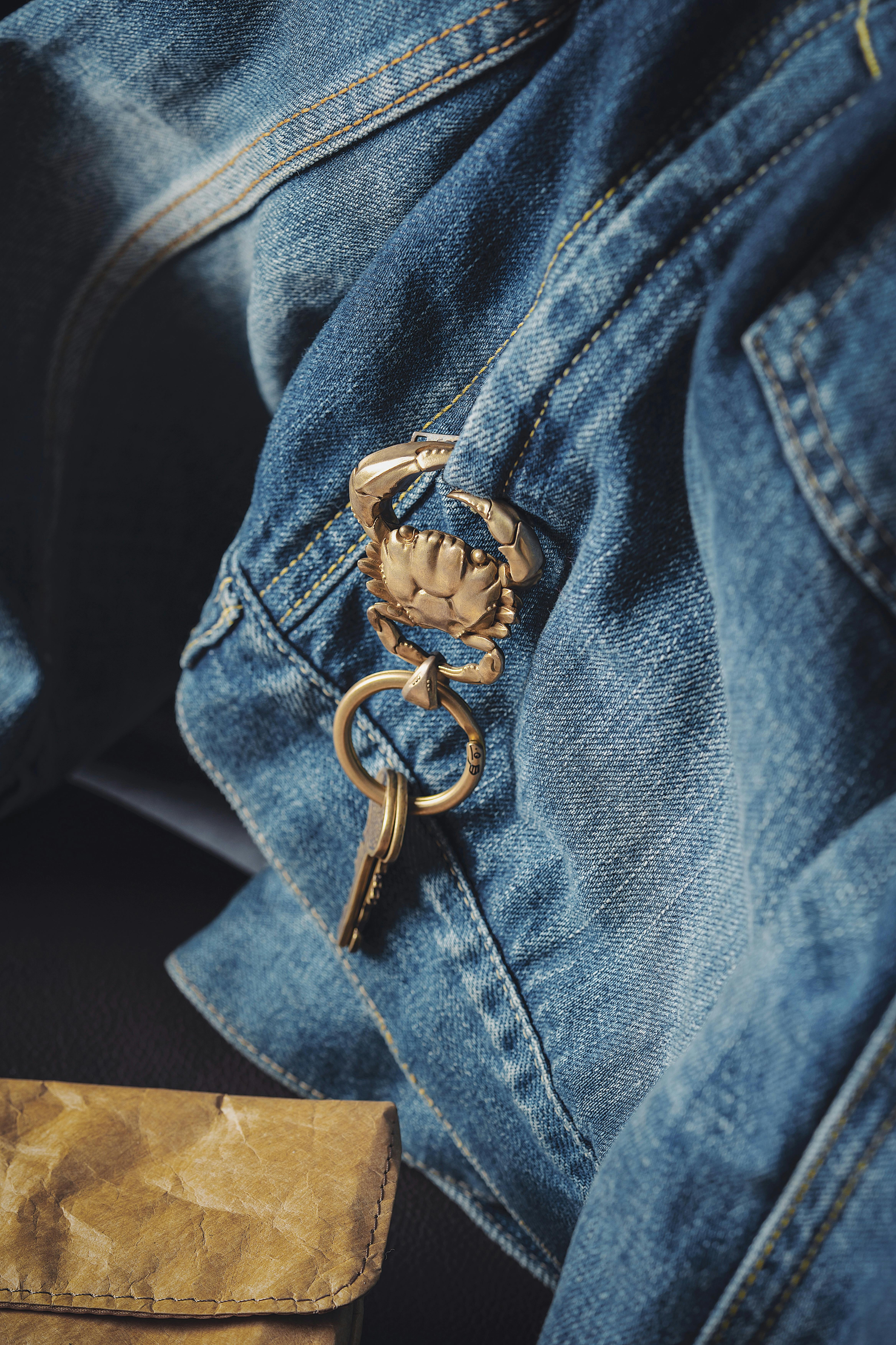 Close-up of a Golden Crab Keychain with Keys Attached to a Denim Jacket ...