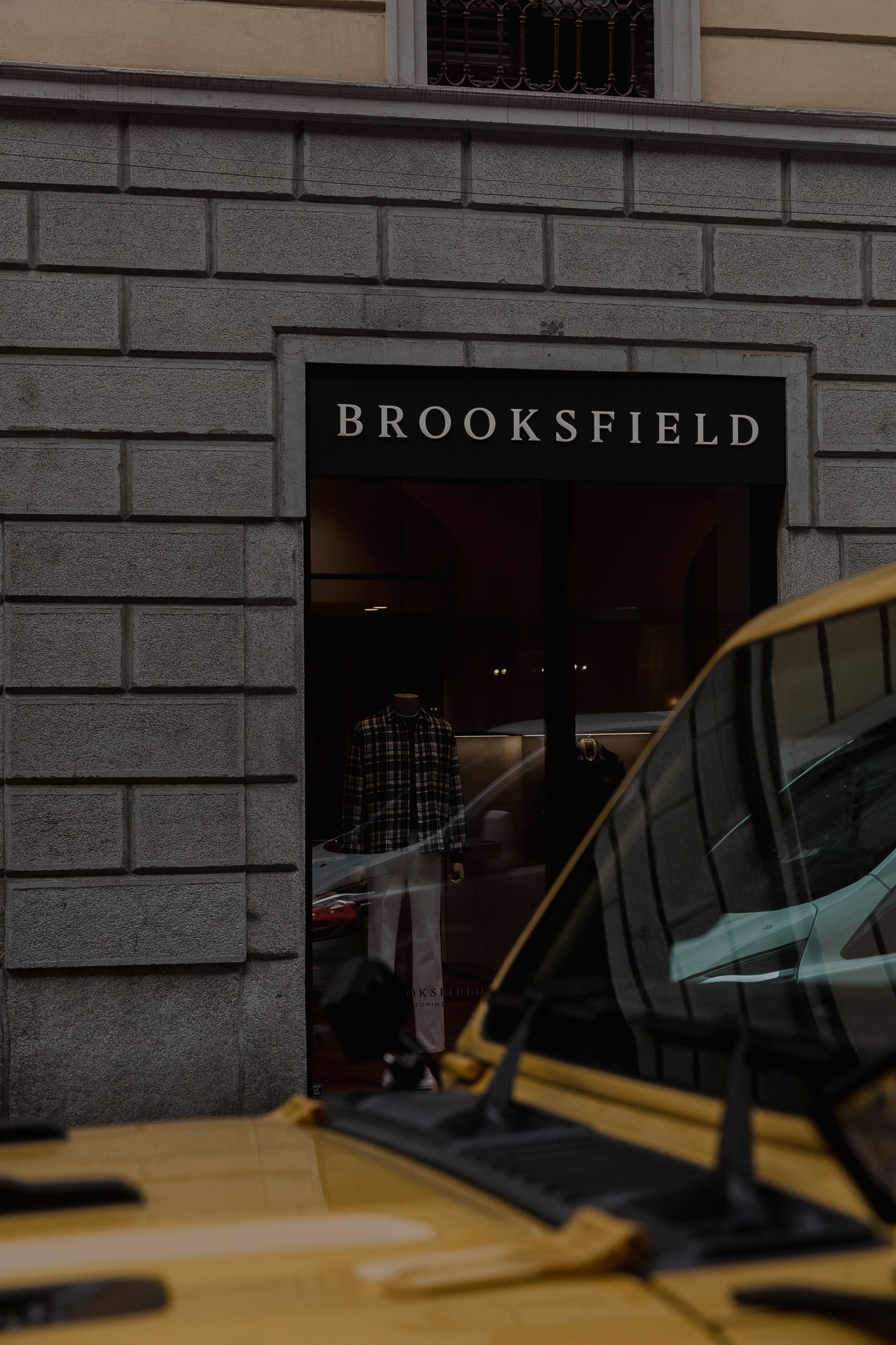 Yellow Car Passing by Storefront Window · Free Stock Photo