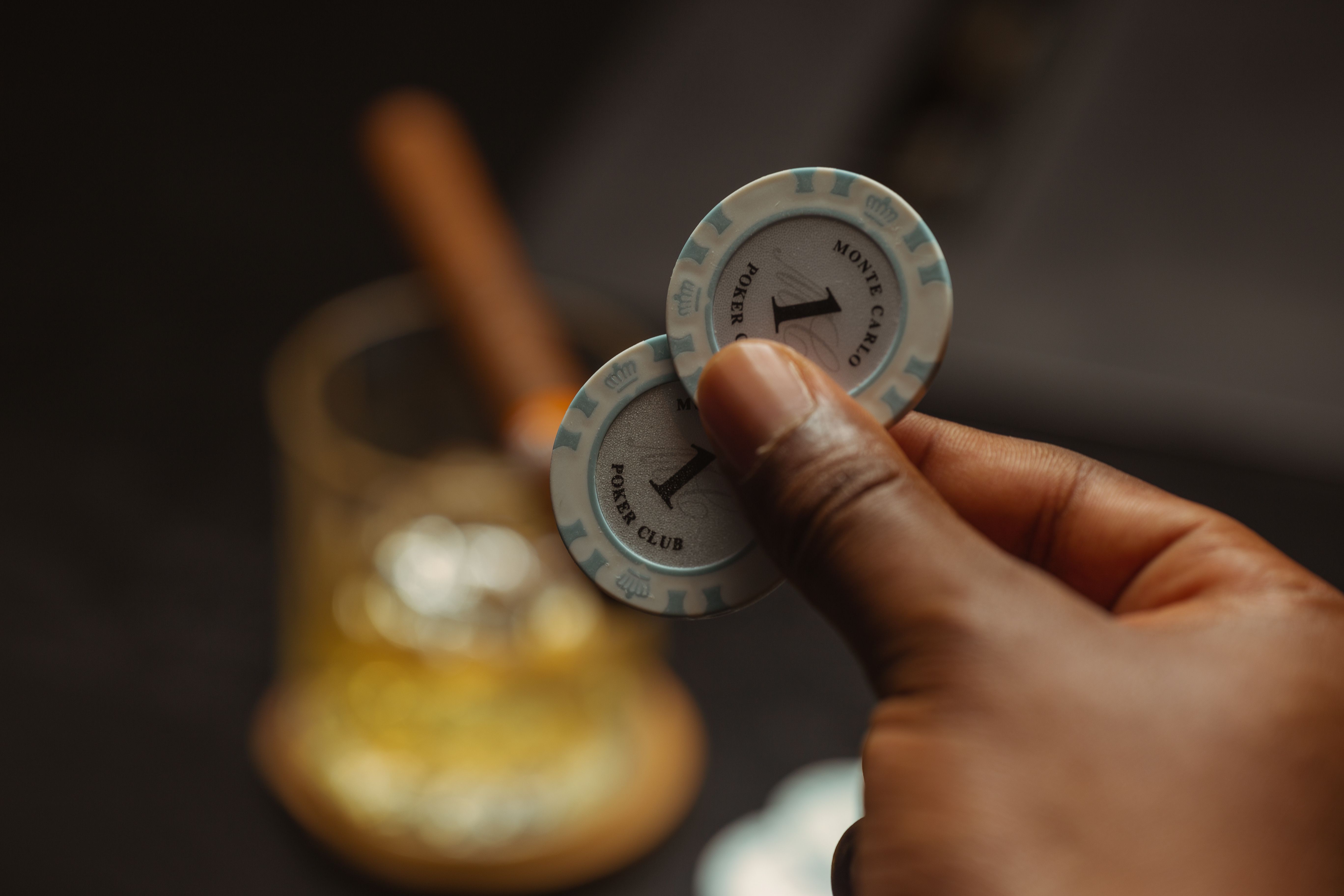 Close-up of Man Holding Casino Tokens on the Background of a Glass with ...