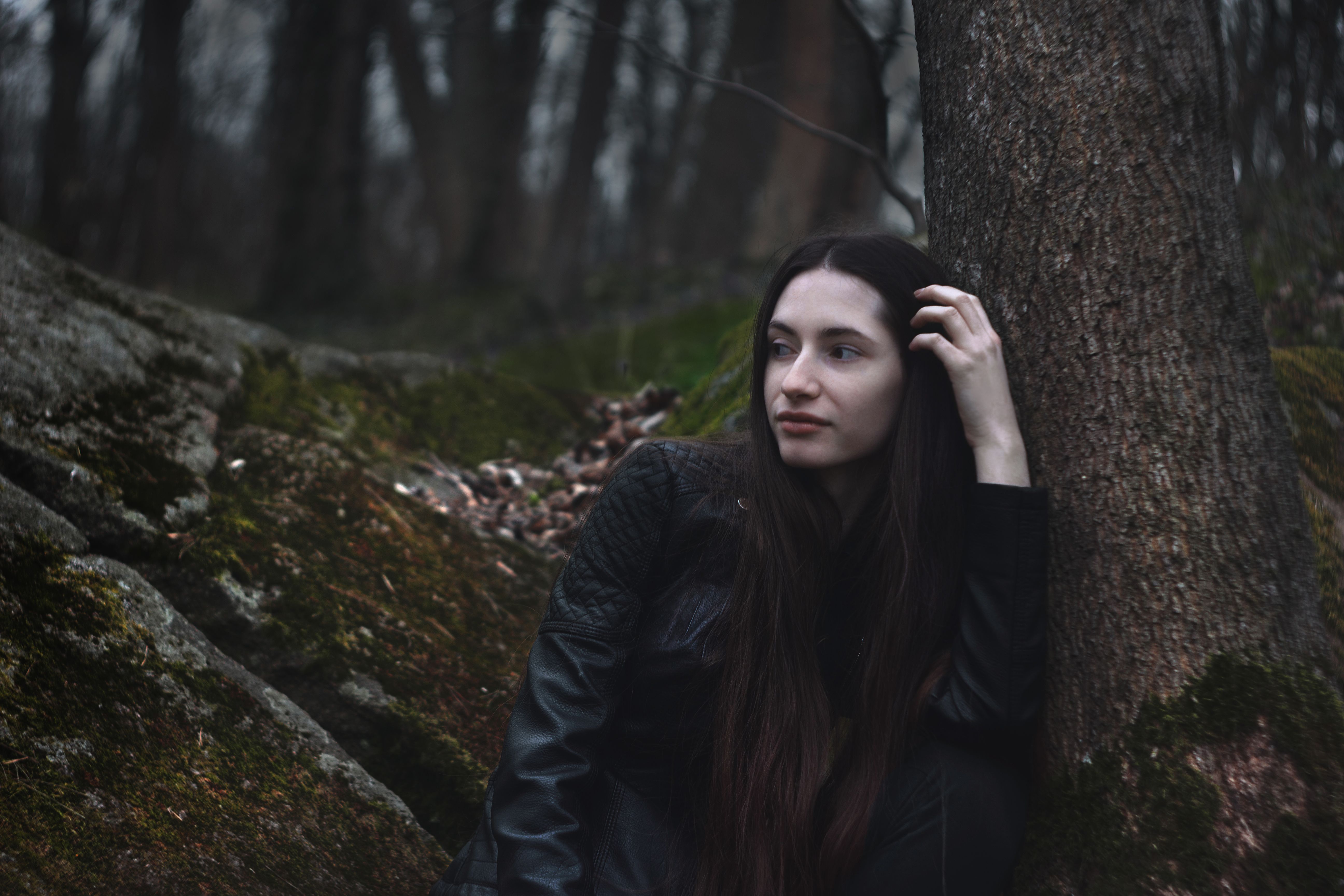 Young Woman Sitting by a Tree in a Forest and Looking Away · Free Stock ...