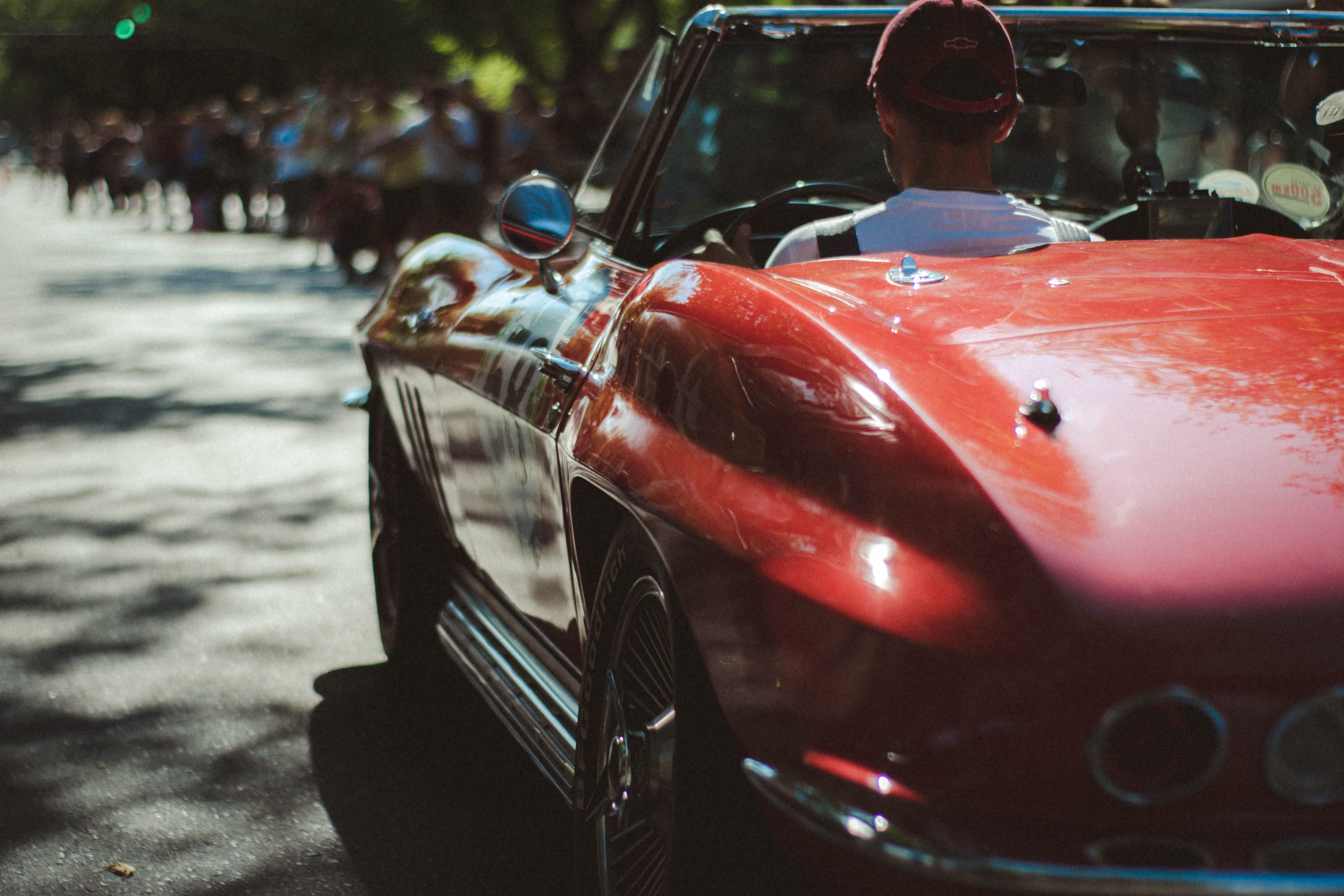 A man in a red convertible car driving down the street · Free Stock Photo