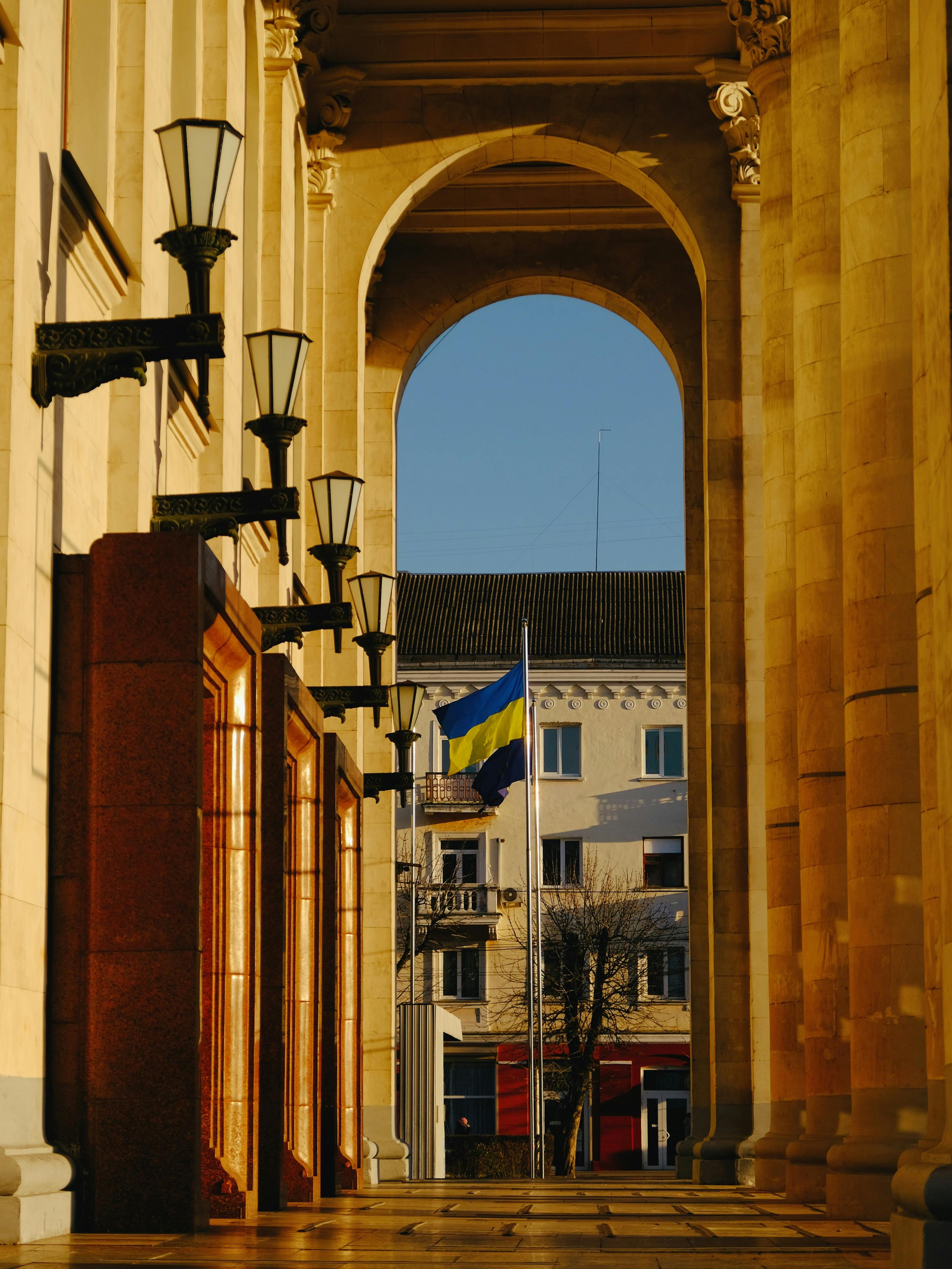 Ukrainian Flag behind Building Columns · Free Stock Photo