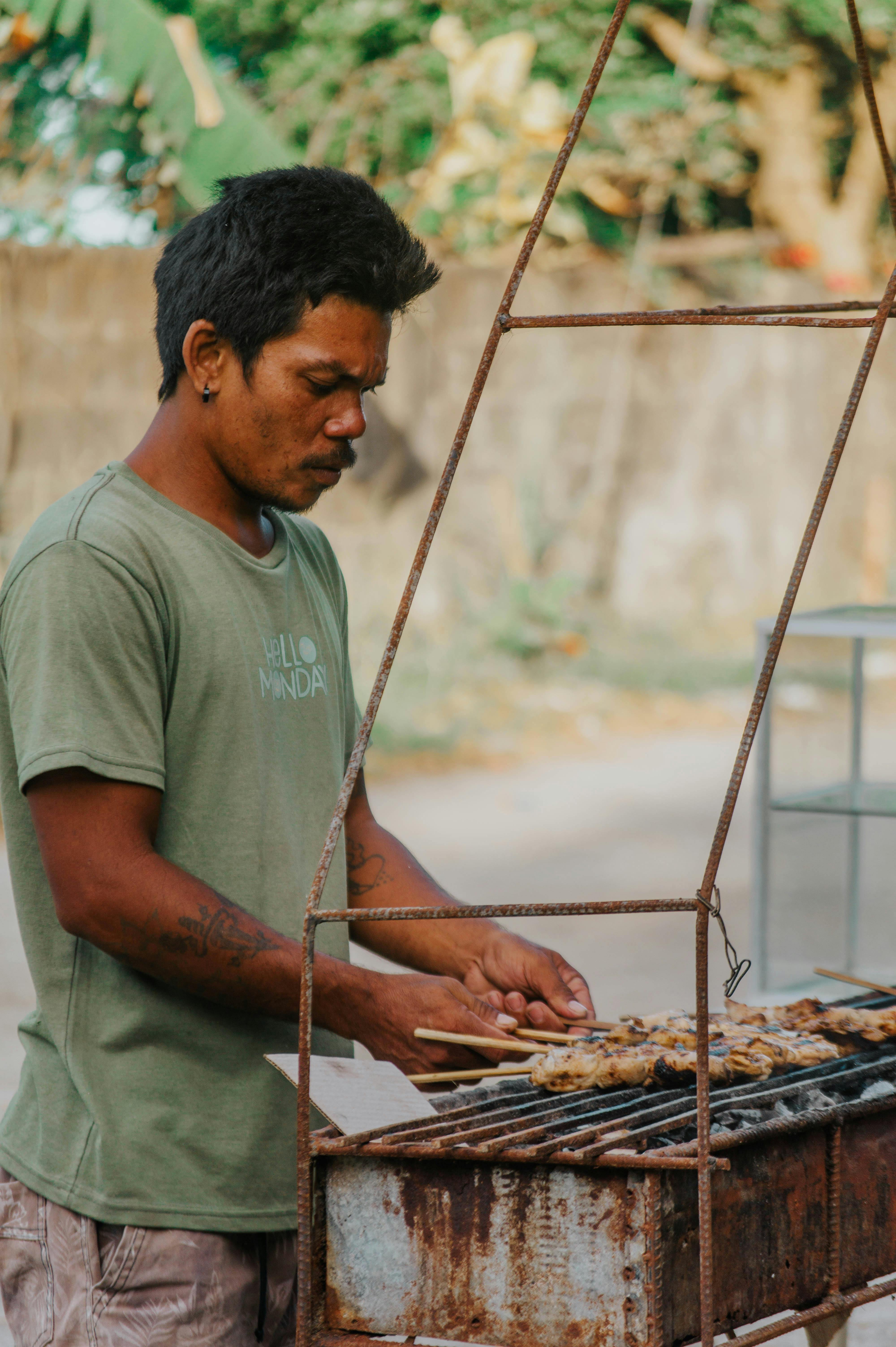 Man in T-shirt Cooking on Barbecue · Free Stock Photo