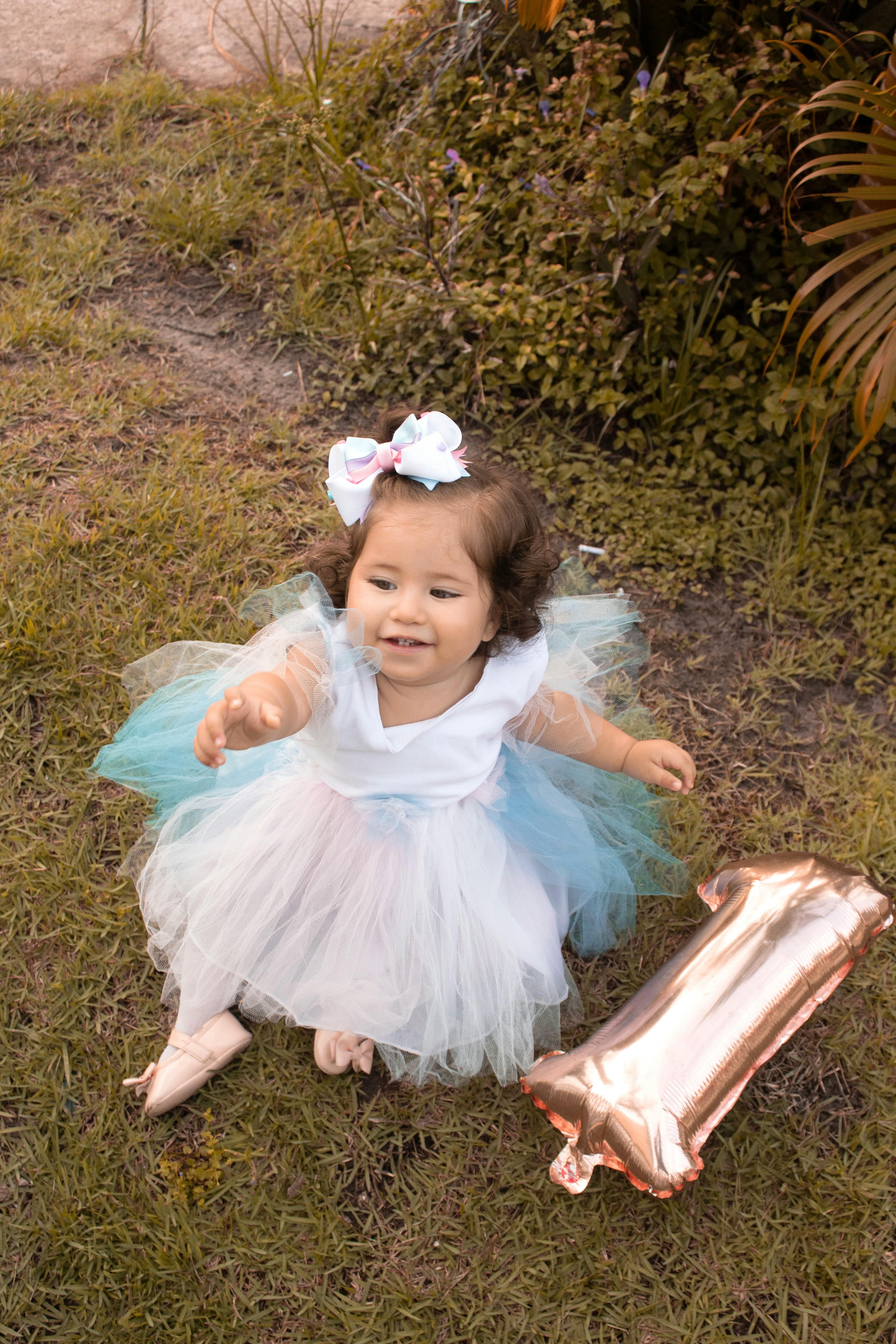 A baby girl in a tutu sitting on the grass · Free Stock Photo