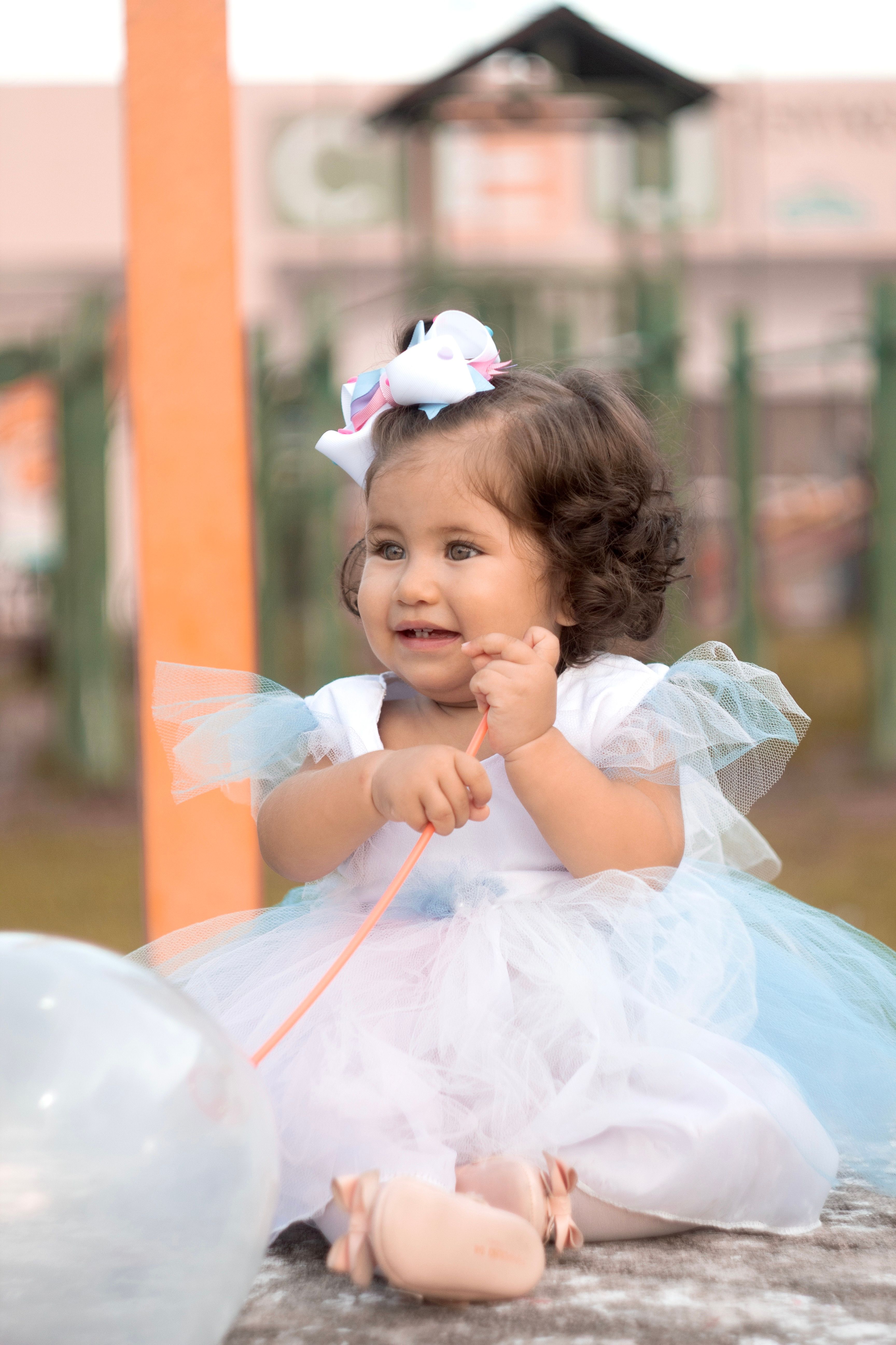 A baby girl in a tutu sitting on a bench · Free Stock Photo