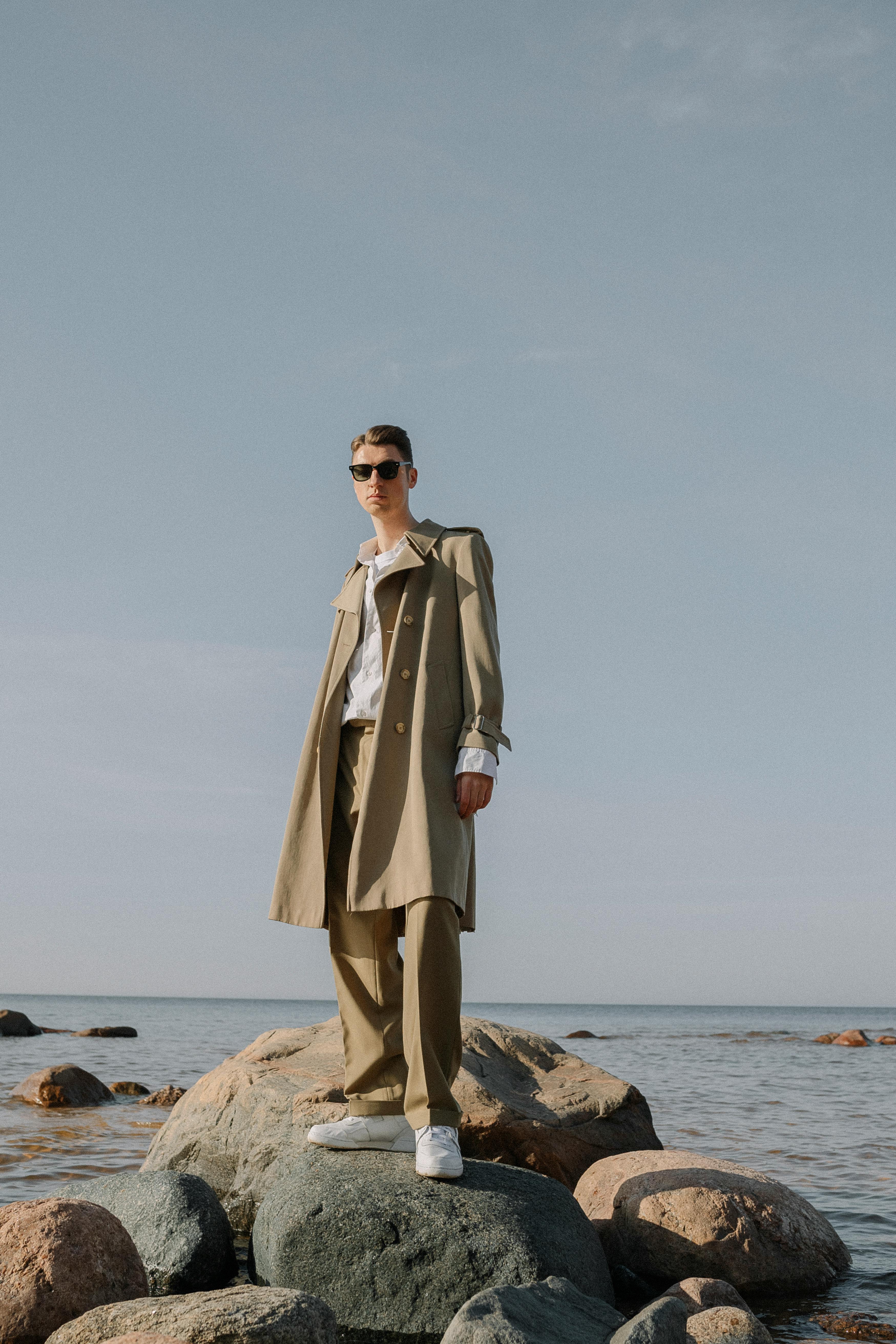 Male Model Posing on Top of Coastal Boulders · Free Stock Photo