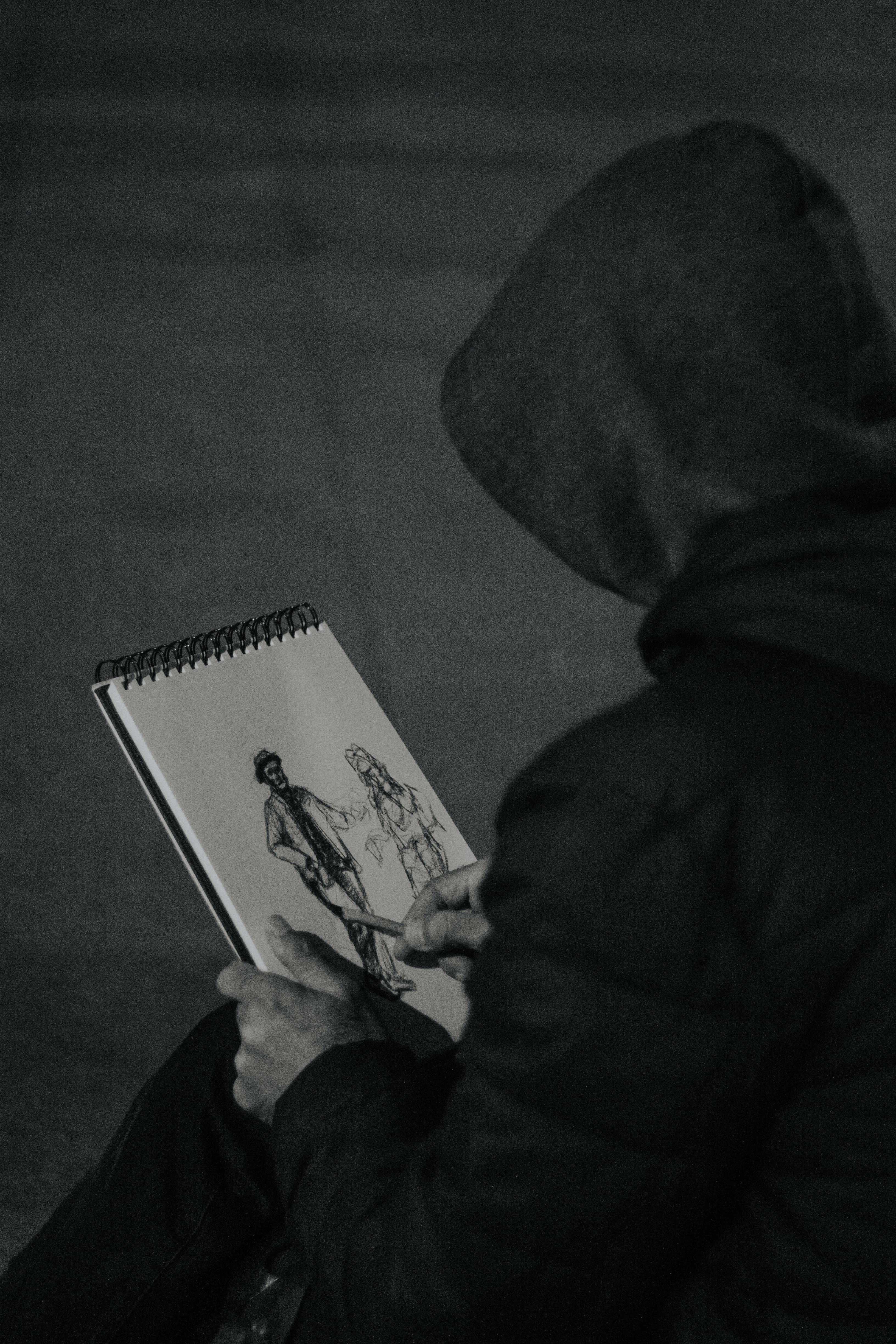Person in Hood Drawing in Notebook · Free Stock Photo