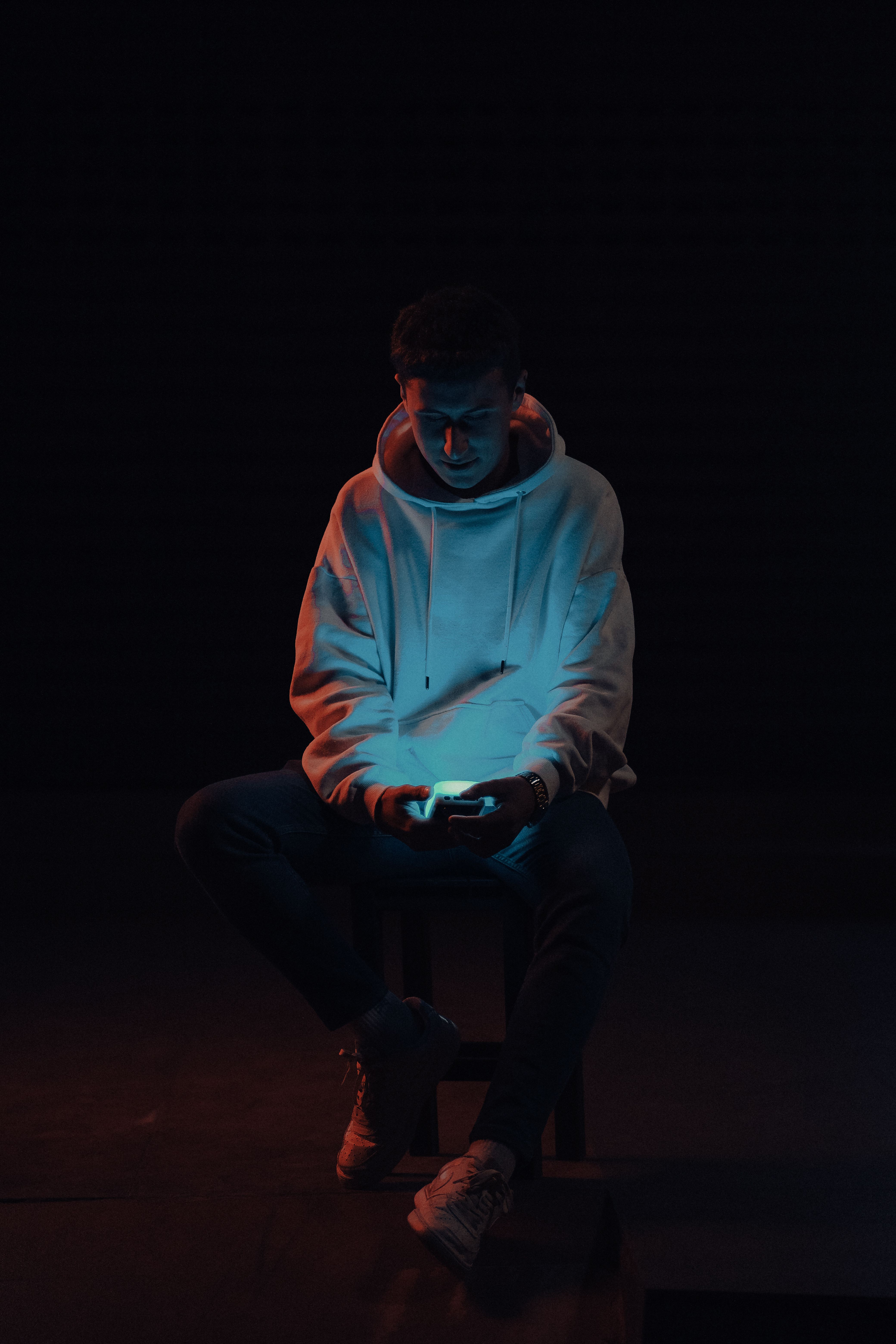 Man Sitting in Darkness Using a Smart Phone · Free Stock Photo