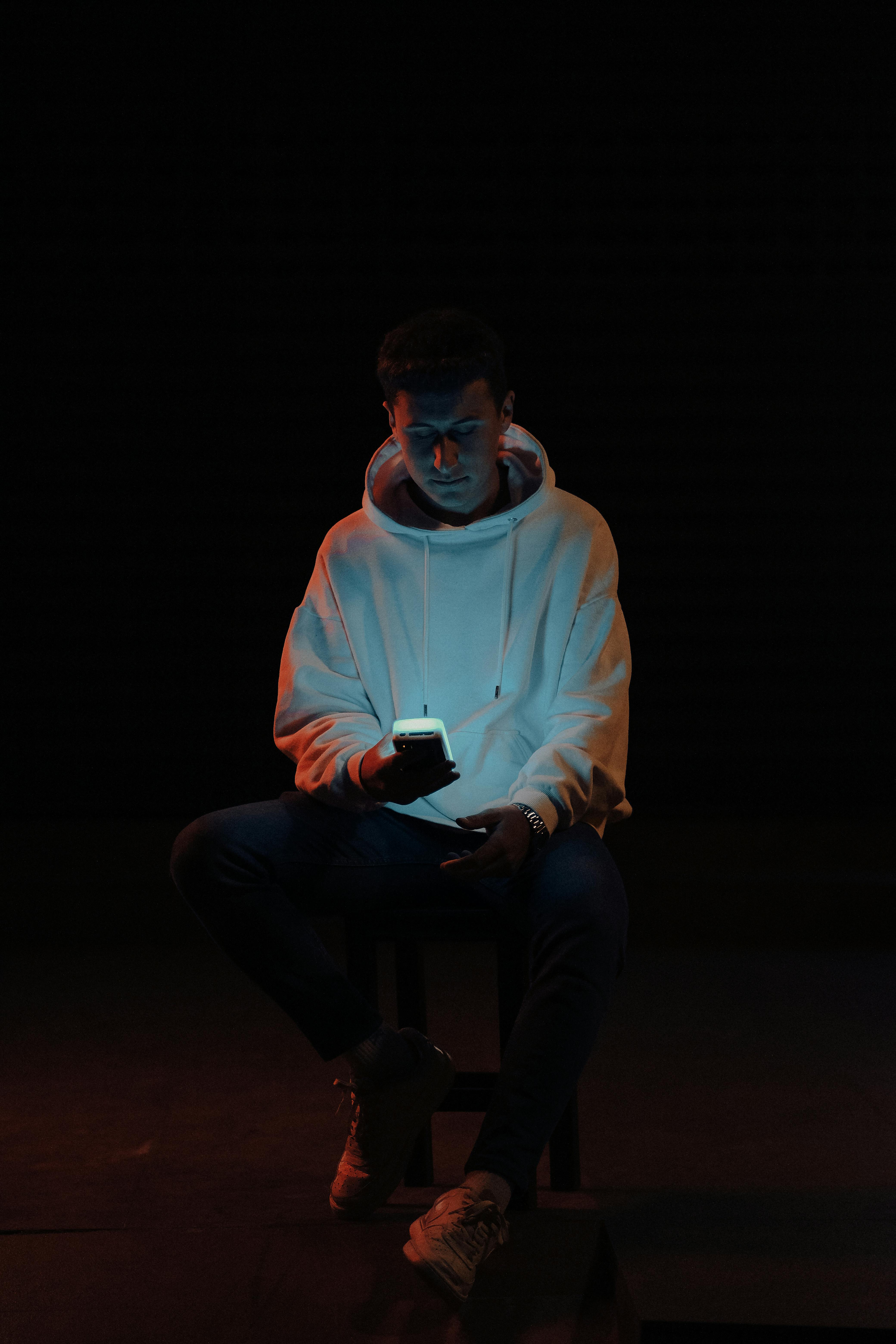 Man Sitting in Dark Room Using Smart Phone · Free Stock Photo