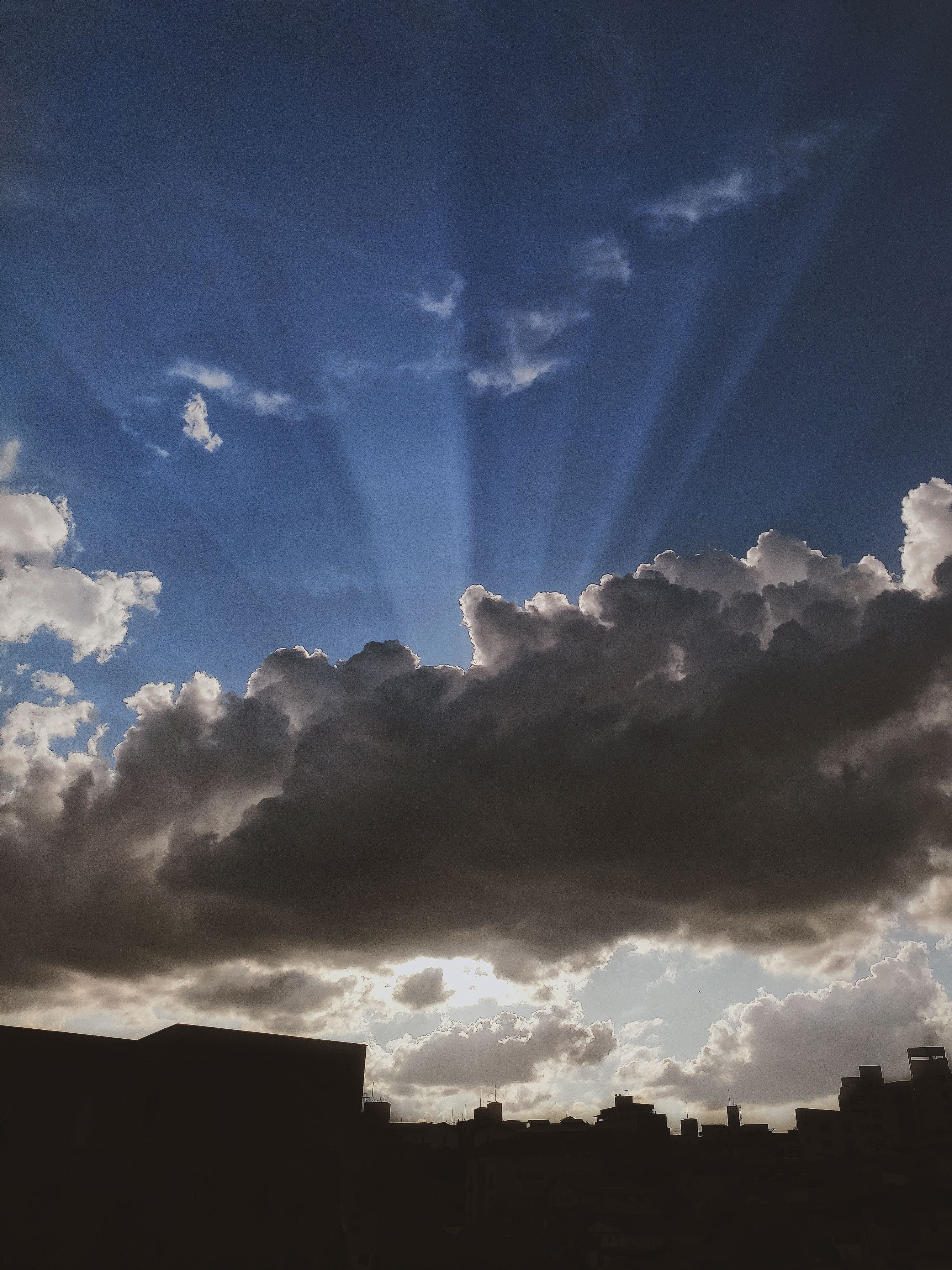 Sunlight behind Clouds over Buildings Silhouette at Sunset · Free Stock ...
