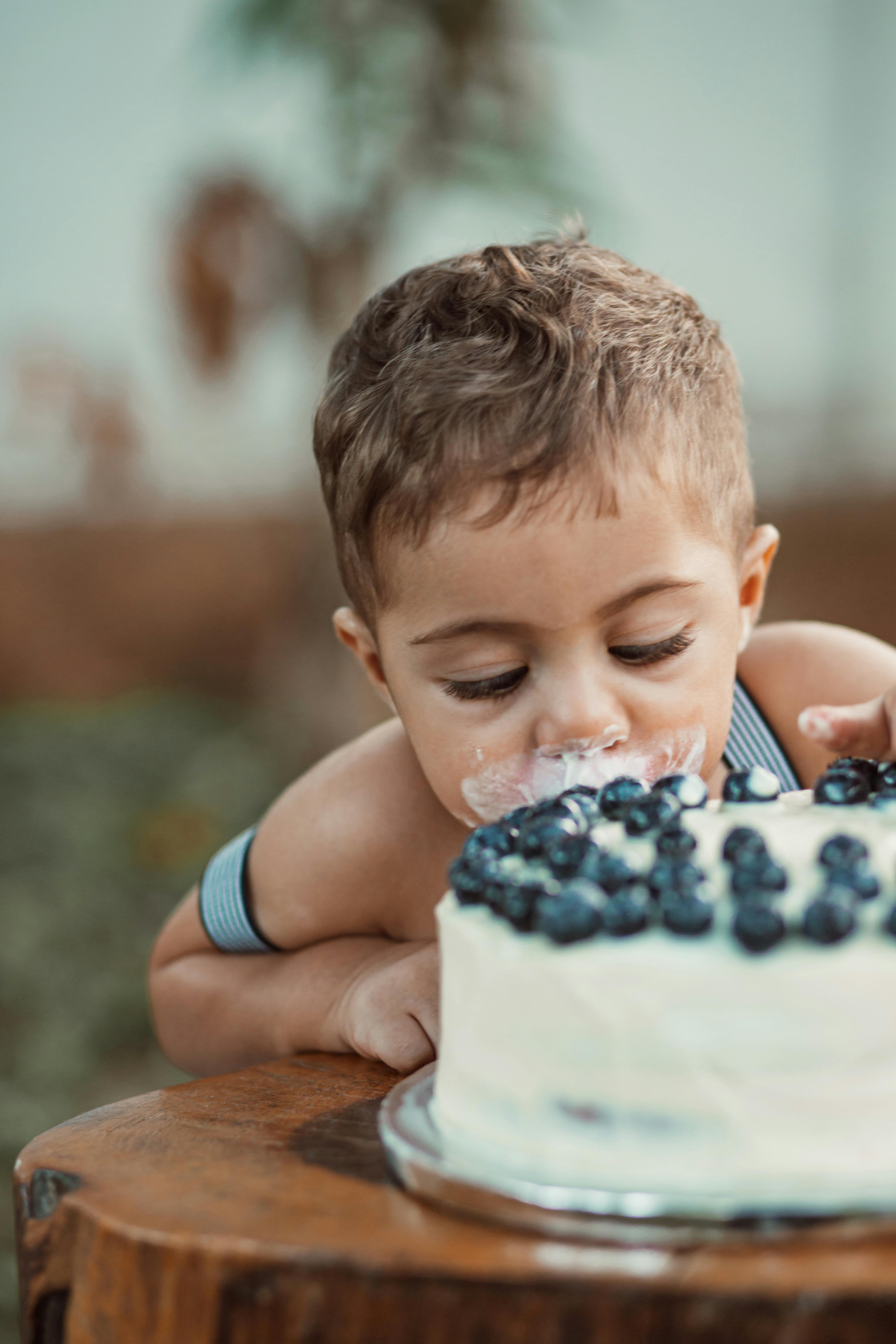 A Little Boy Biting into a Whole Cake · Free Stock Photo