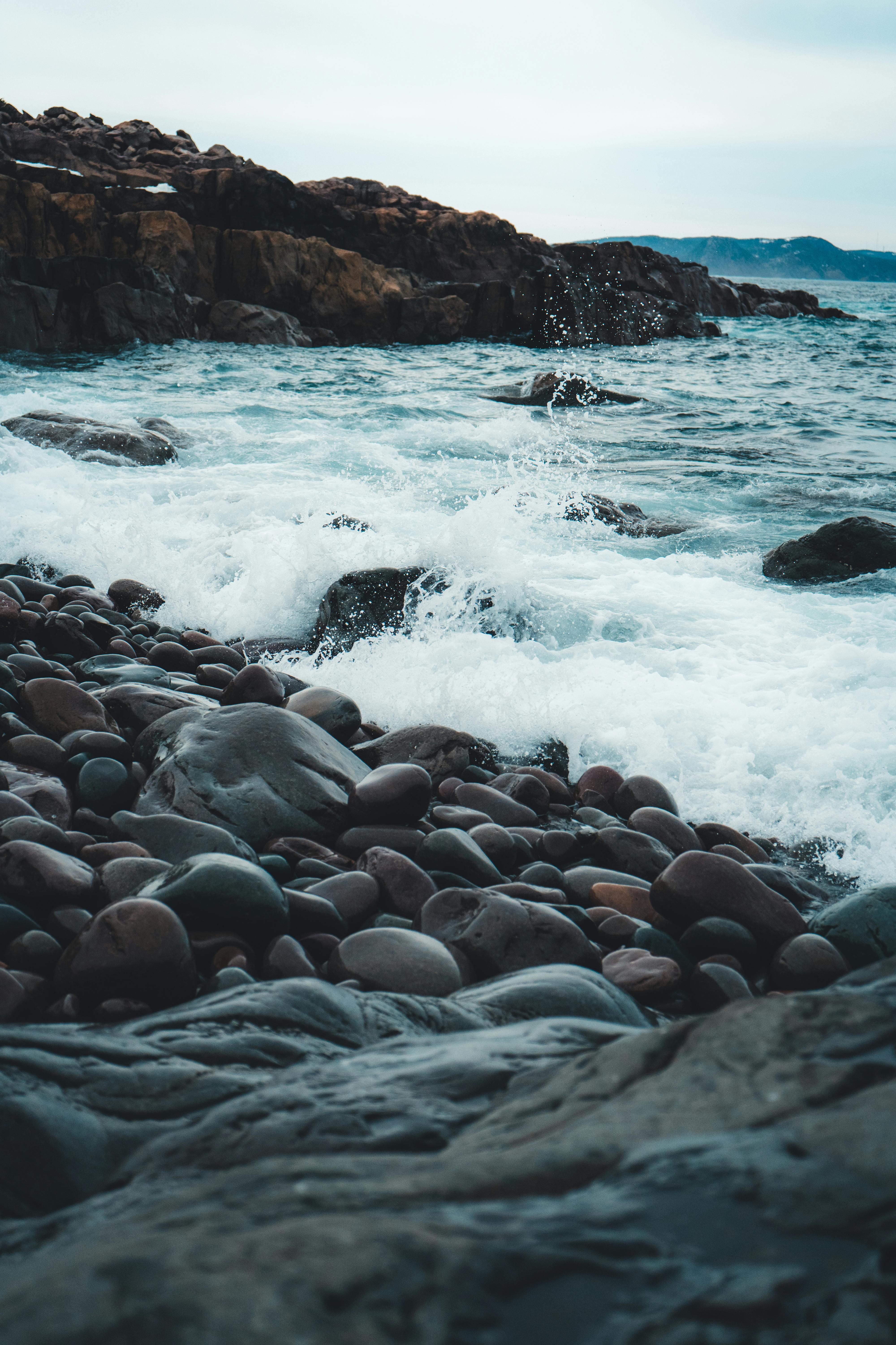 Waves Crashing on Shore Covered in Smooth Stones · Free Stock Photo