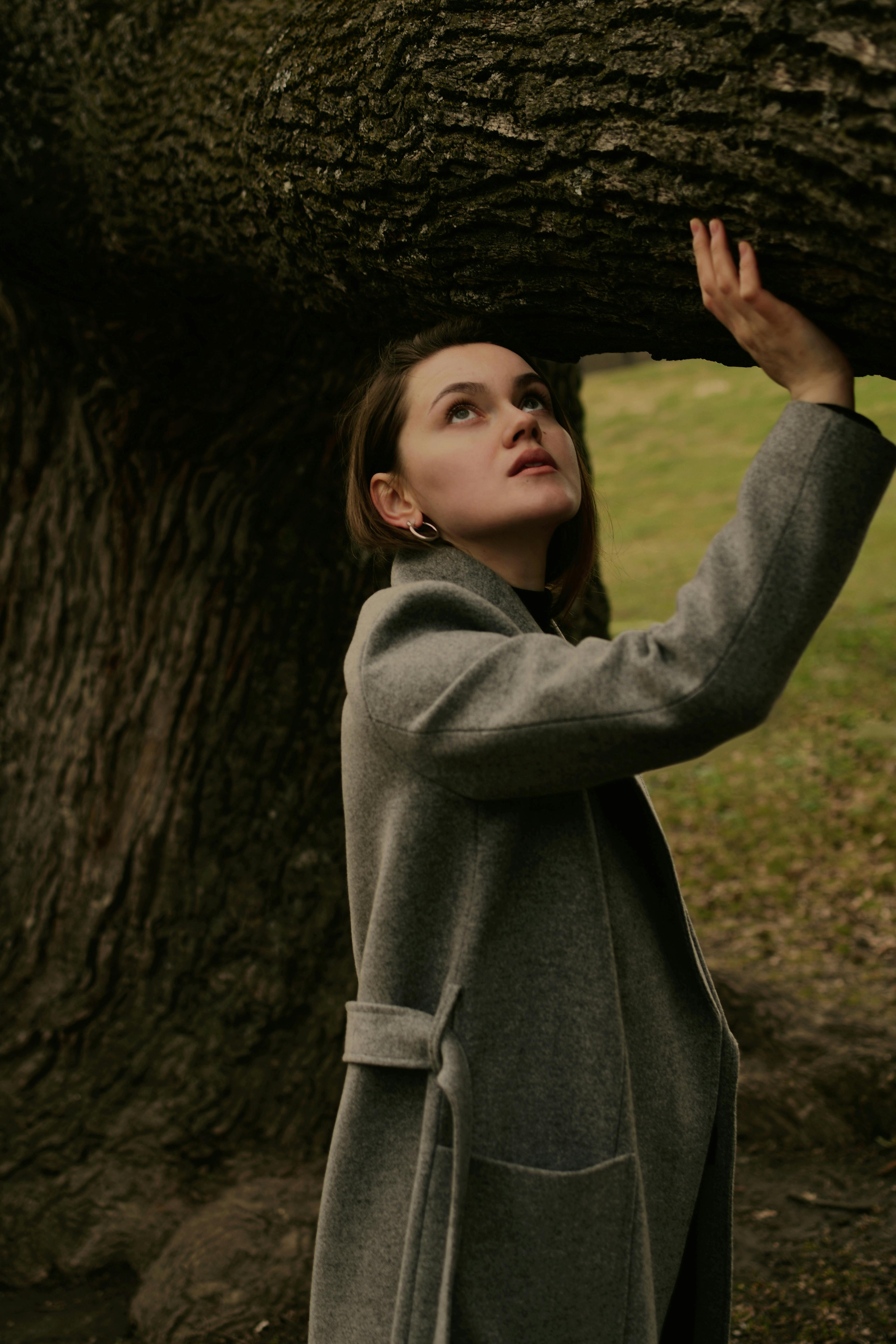 Woman in Coat Standing under Tree Trunk · Free Stock Photo