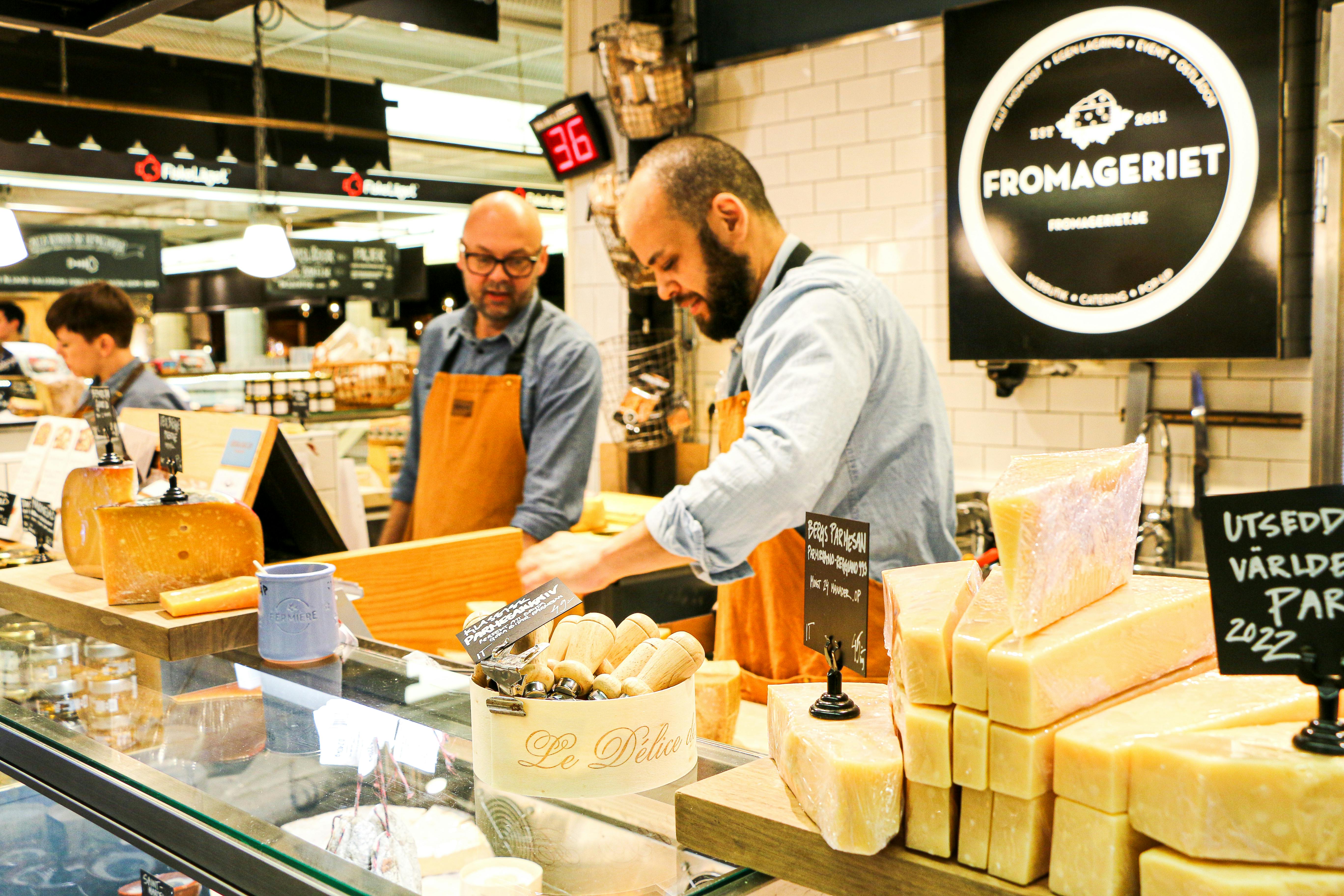 Men in Aprons Standing behind the Counter at a Food Stall with Cheese ...