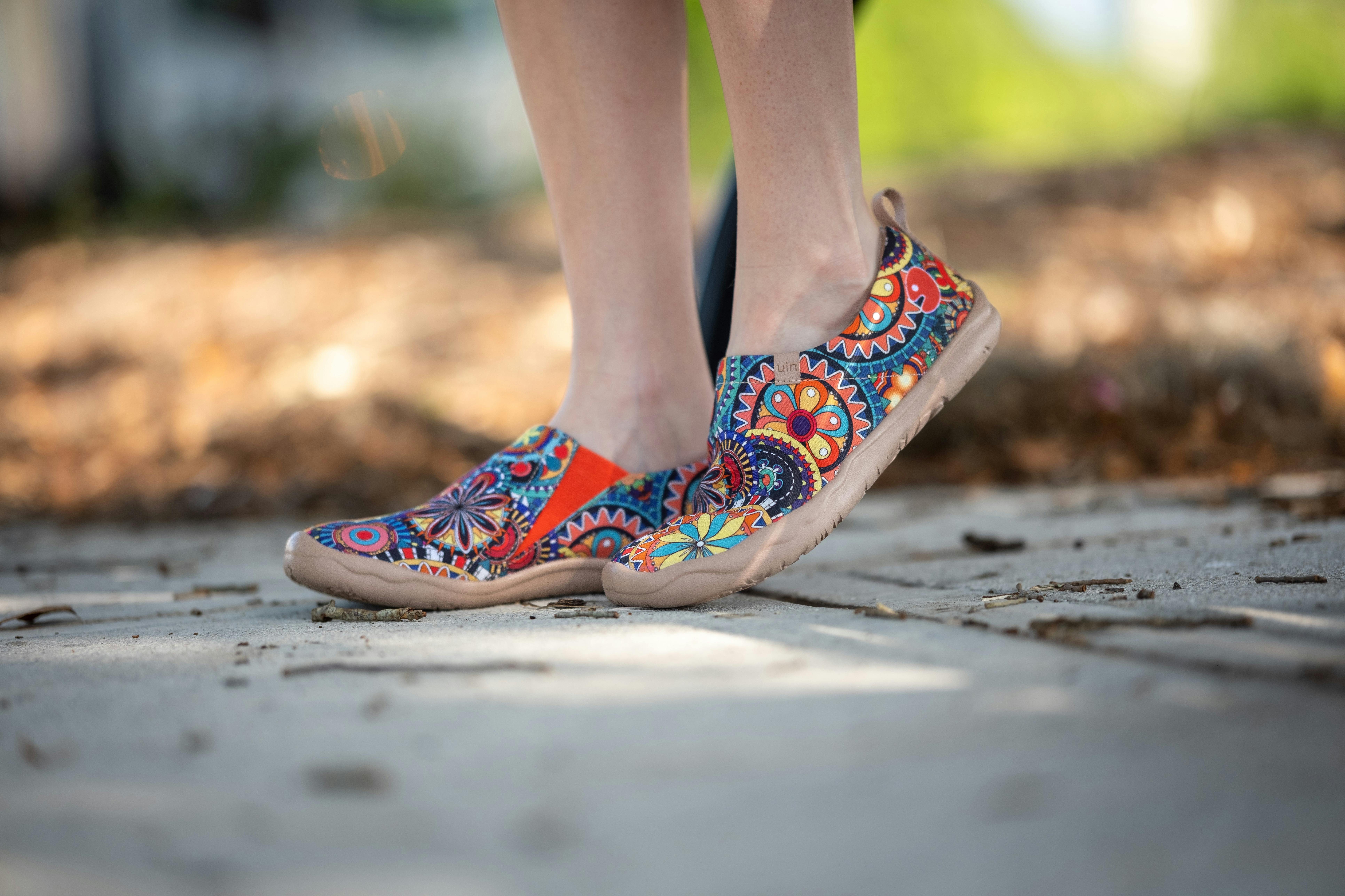 A woman's feet in colorful shoes on a sidewalk · Free Stock Photo