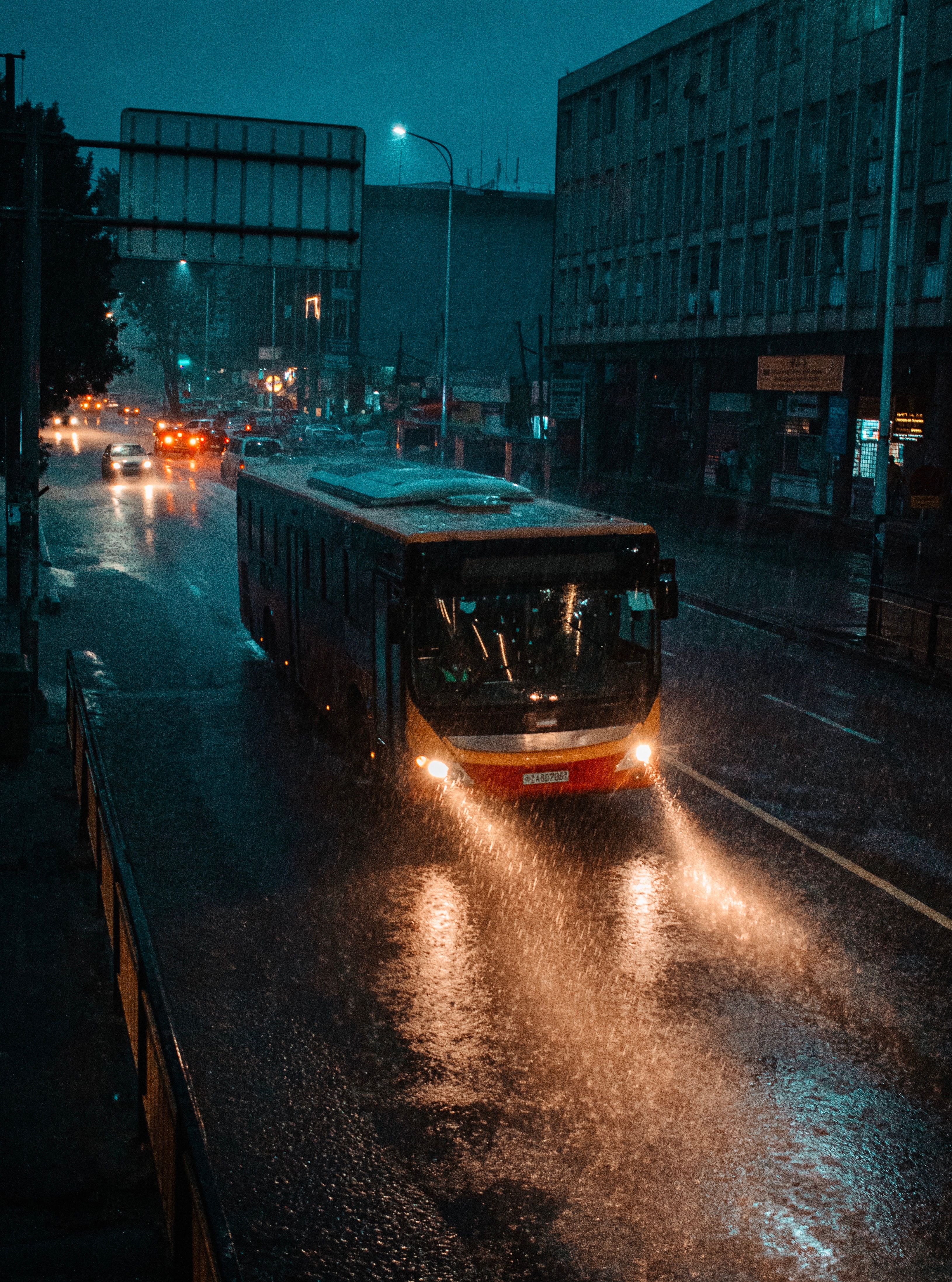 A bus driving down a street in the rain · Free Stock Photo