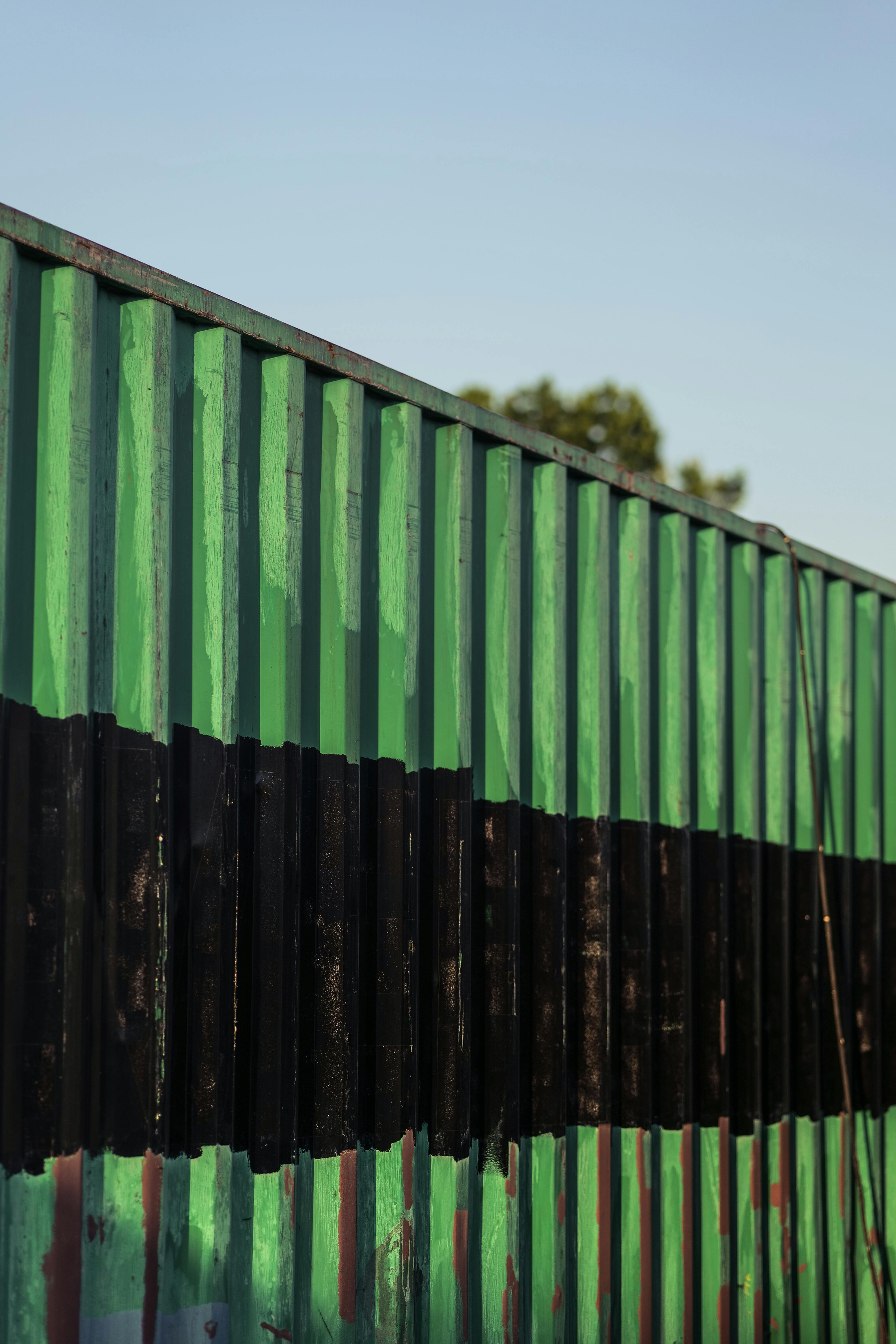 A green and black fence with a black stripe · Free Stock Photo