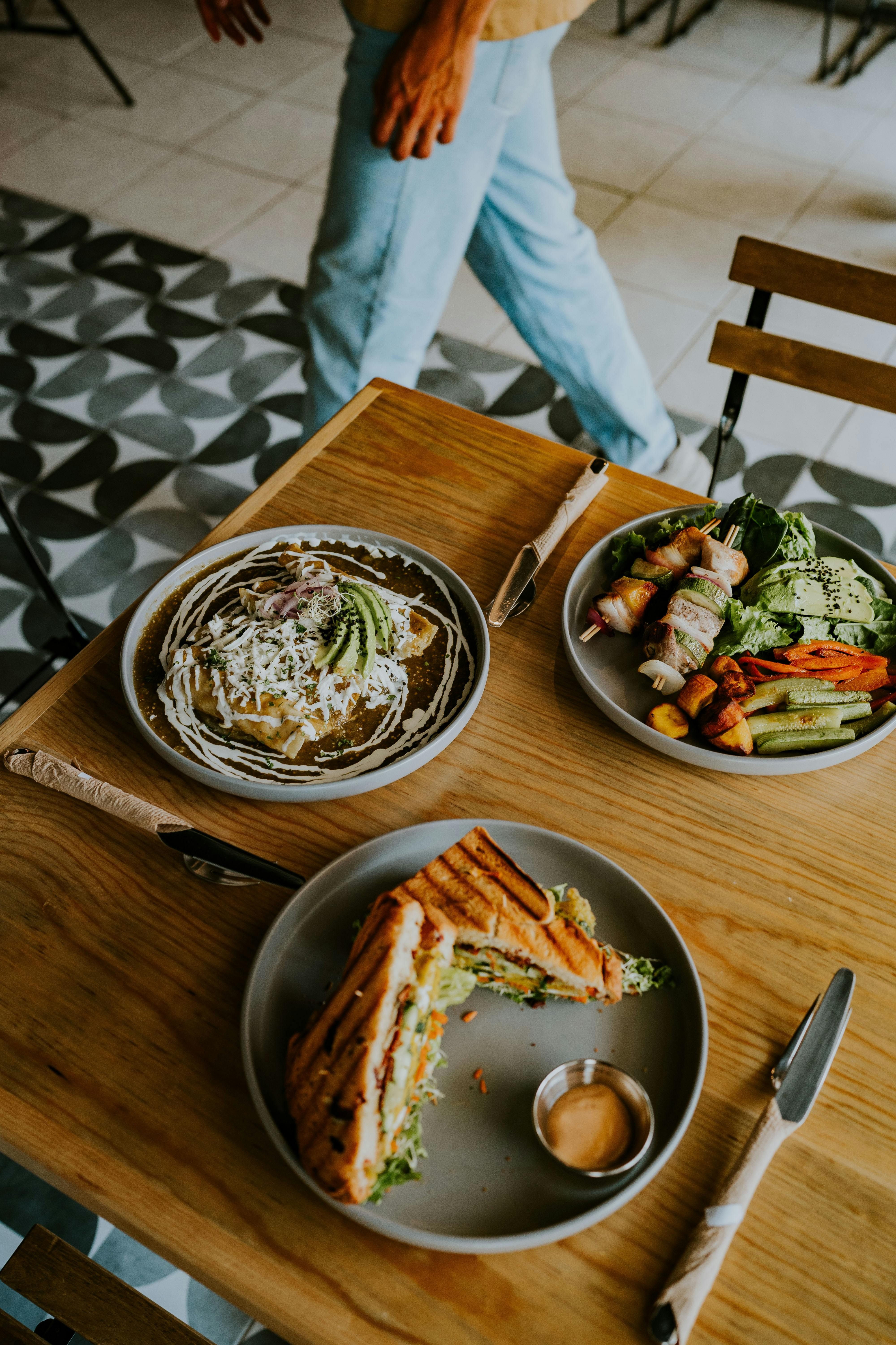 A person walking on a wooden table with plates of food · Free Stock Photo
