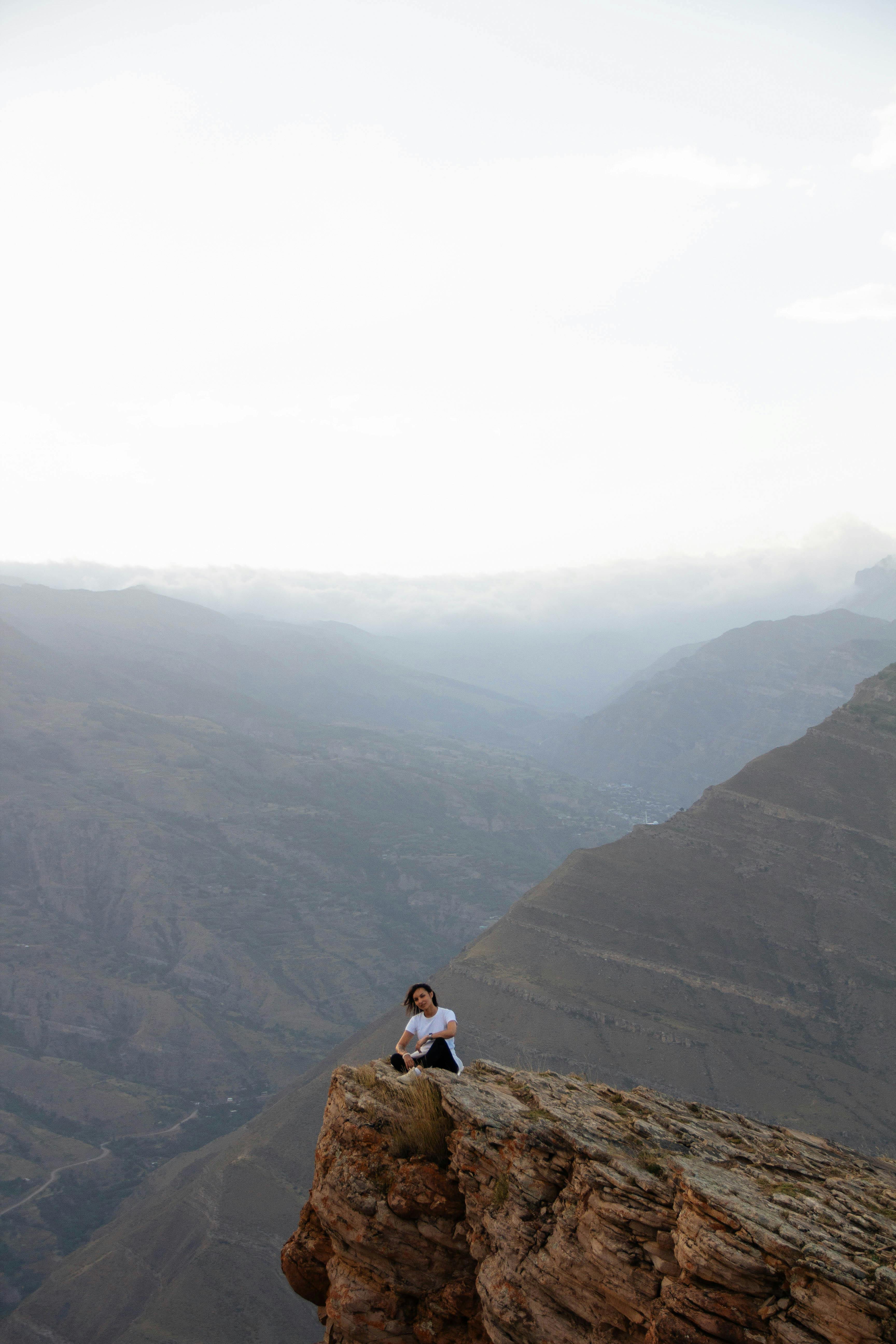 Hiker Sitting on a Rock Overhang in the Mountains · Free Stock Photo