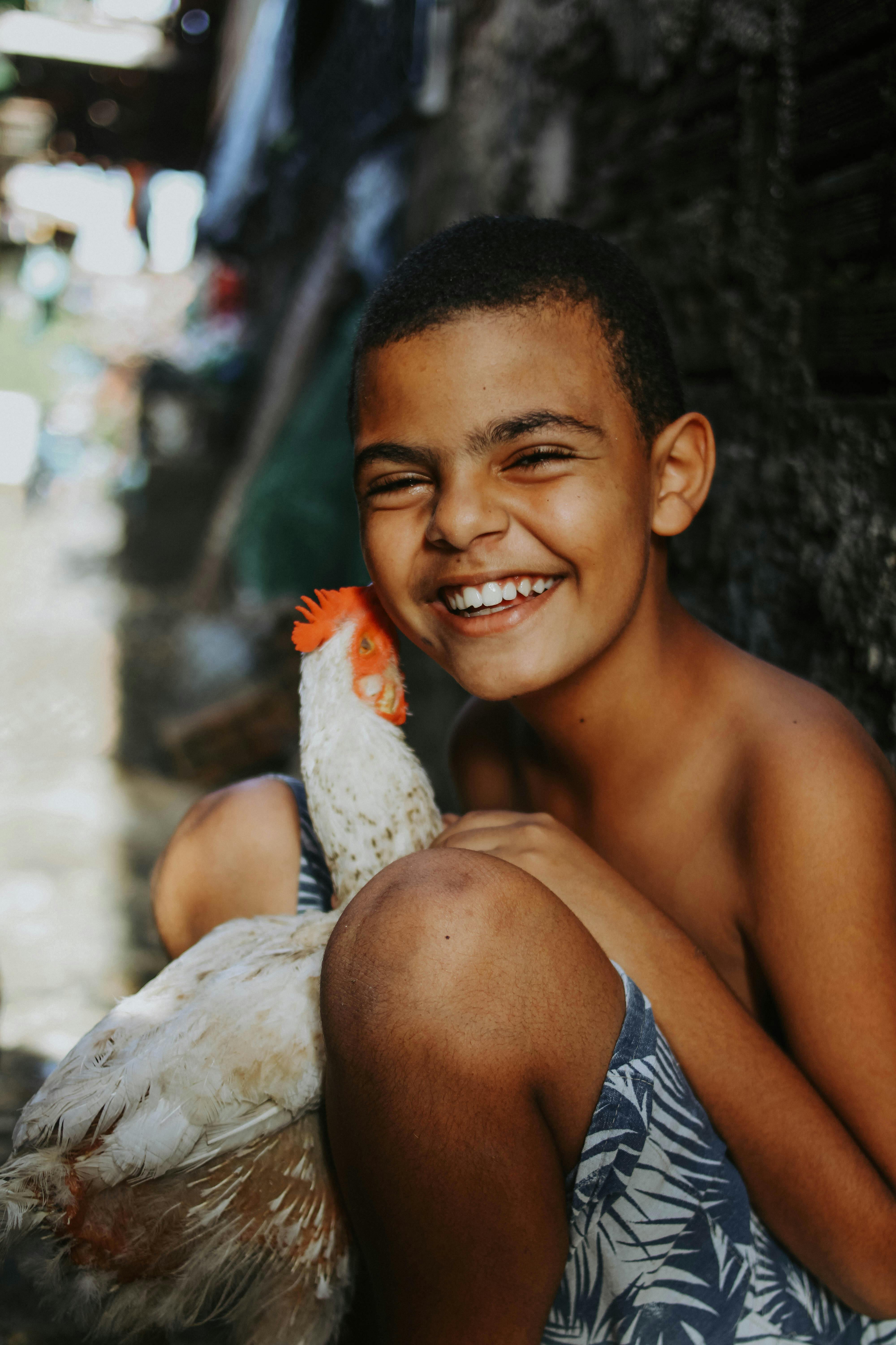Joyful Child Hugging a Chicken Outdoors · Free Stock Photo