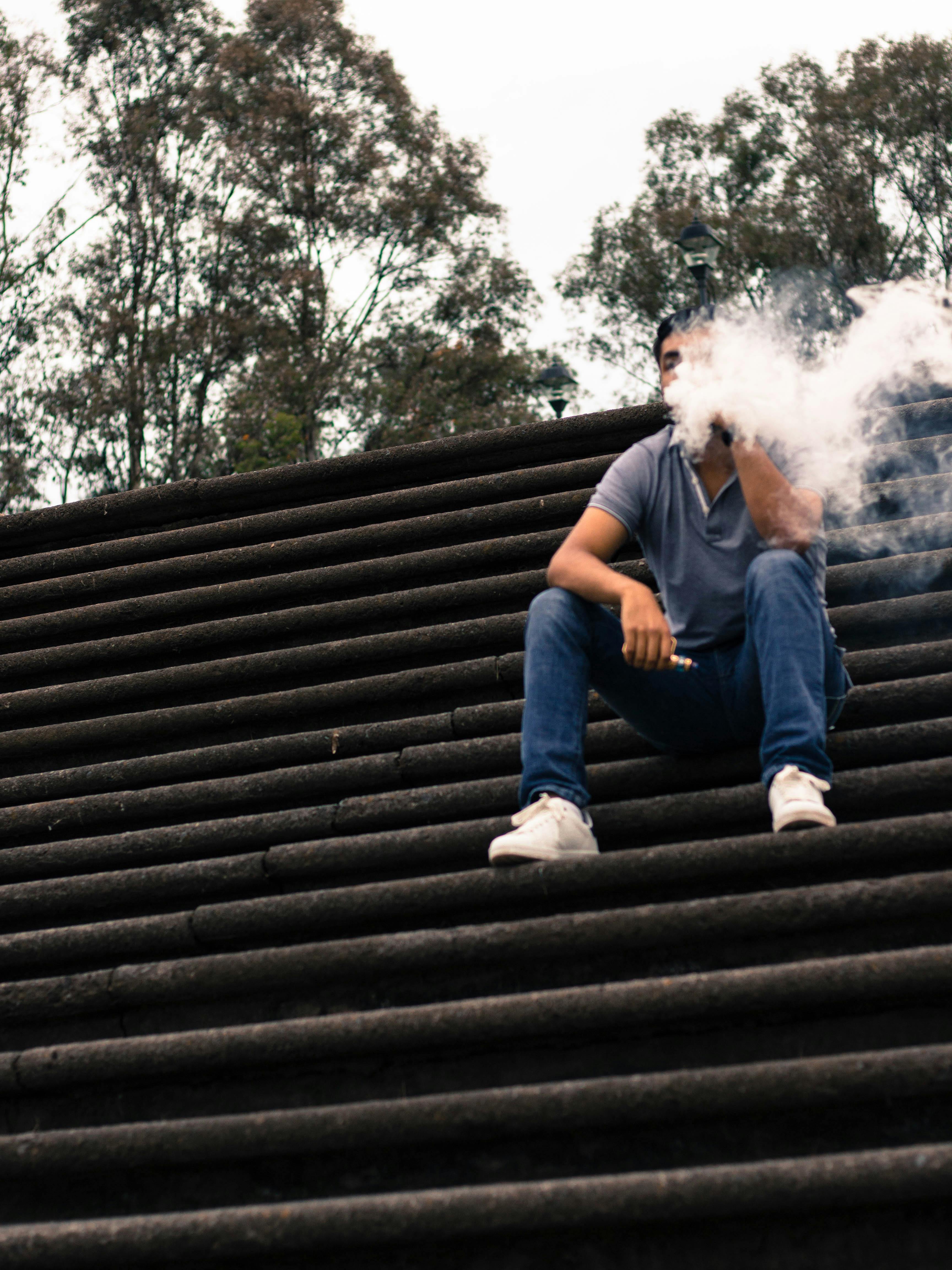Man Sitting on Stairs Smoking Vaporizer · Free Stock Photo