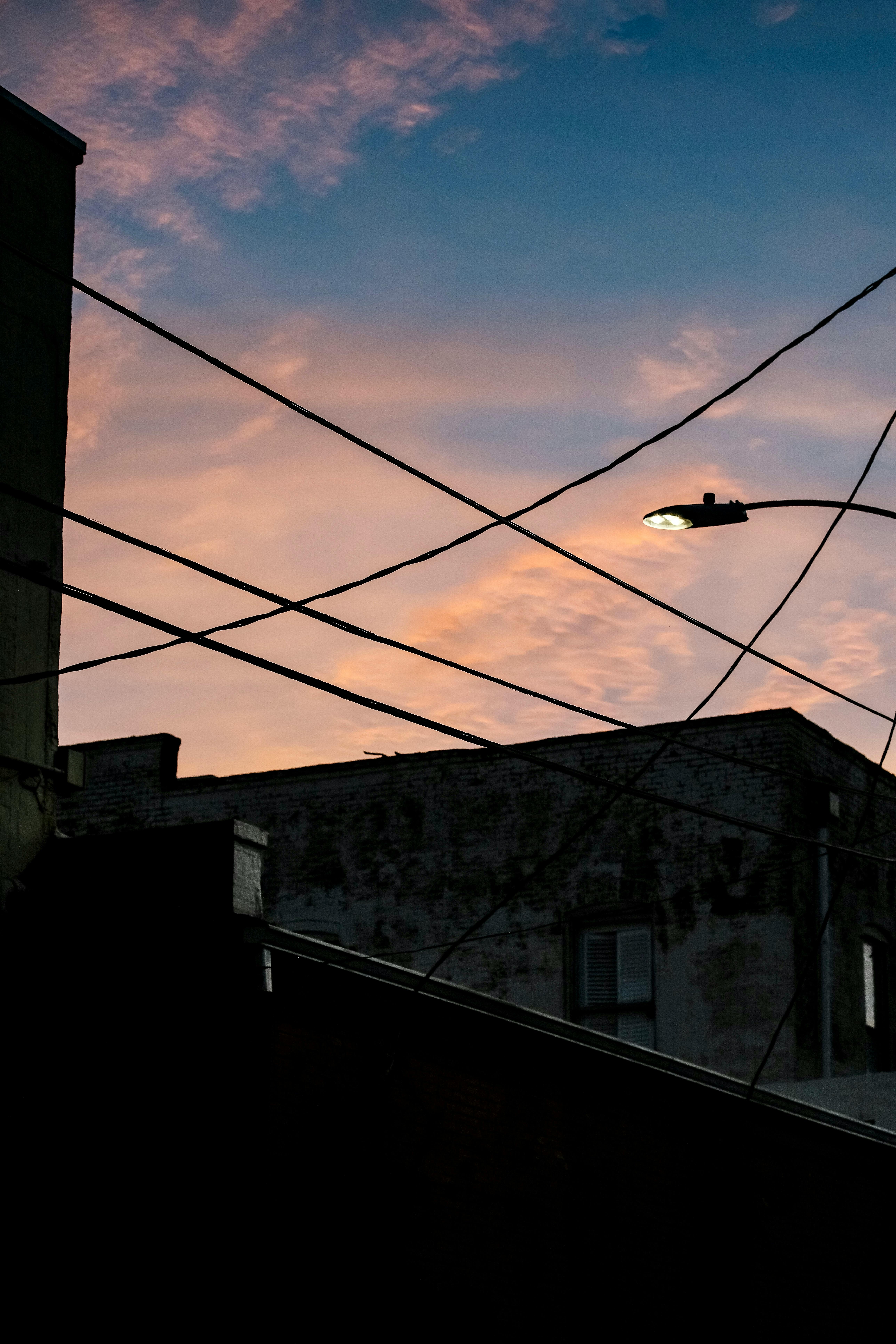 A street light and power lines in front of a sunset · Free Stock Photo