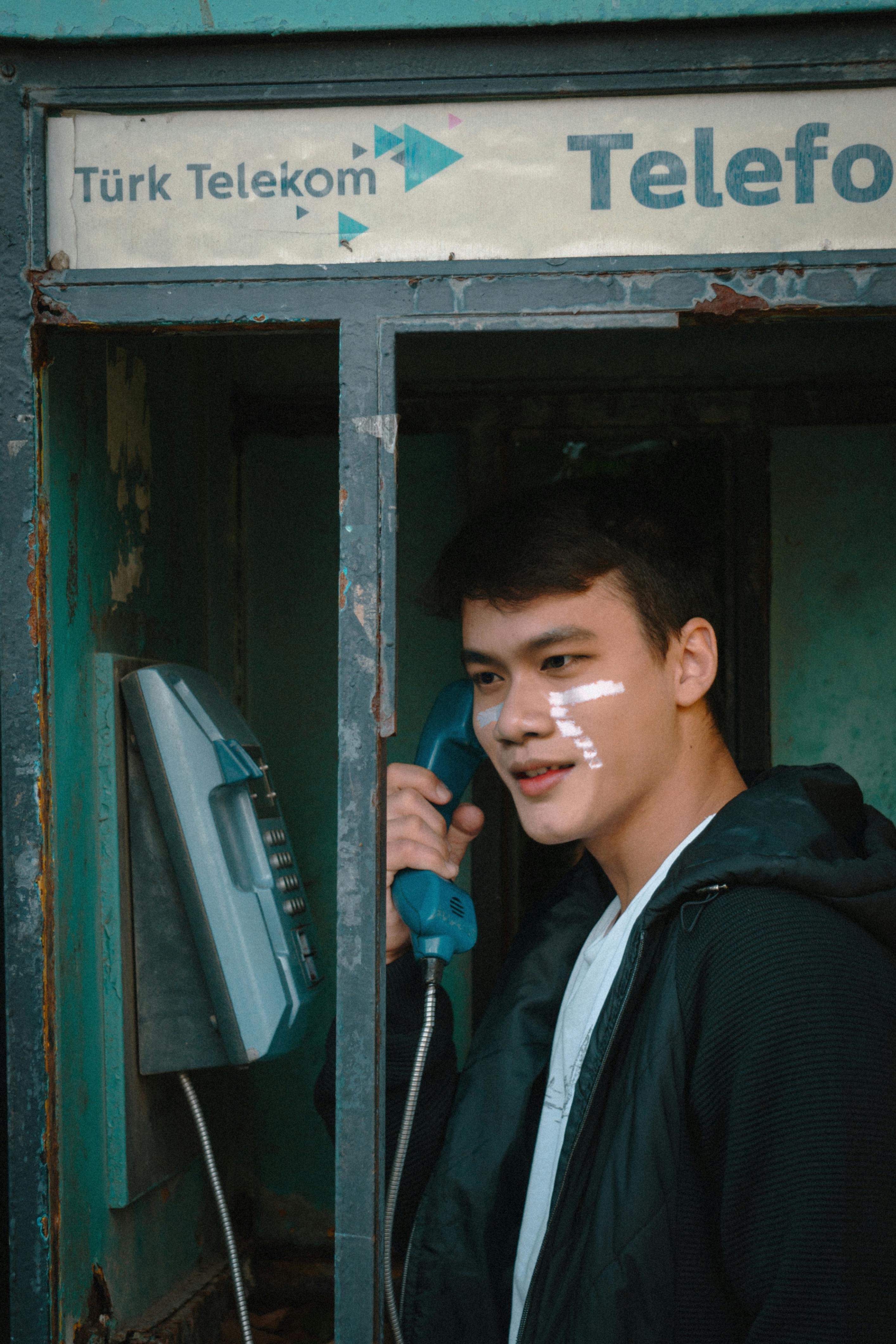 Young Man Using a Vintage Pay Phone · Free Stock Photo