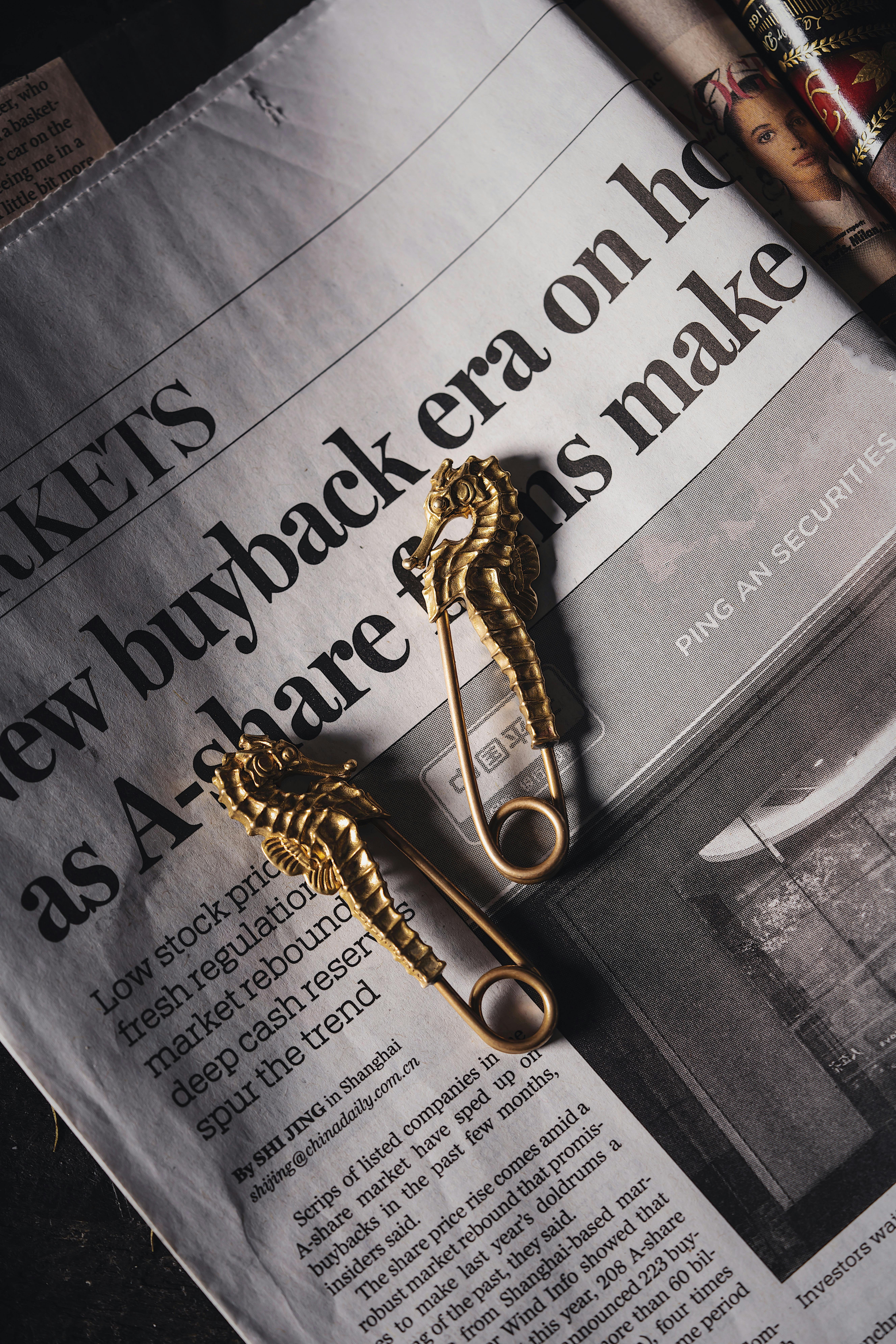 Golden Pins in Shape of Seahorse on Newspaper · Free Stock Photo