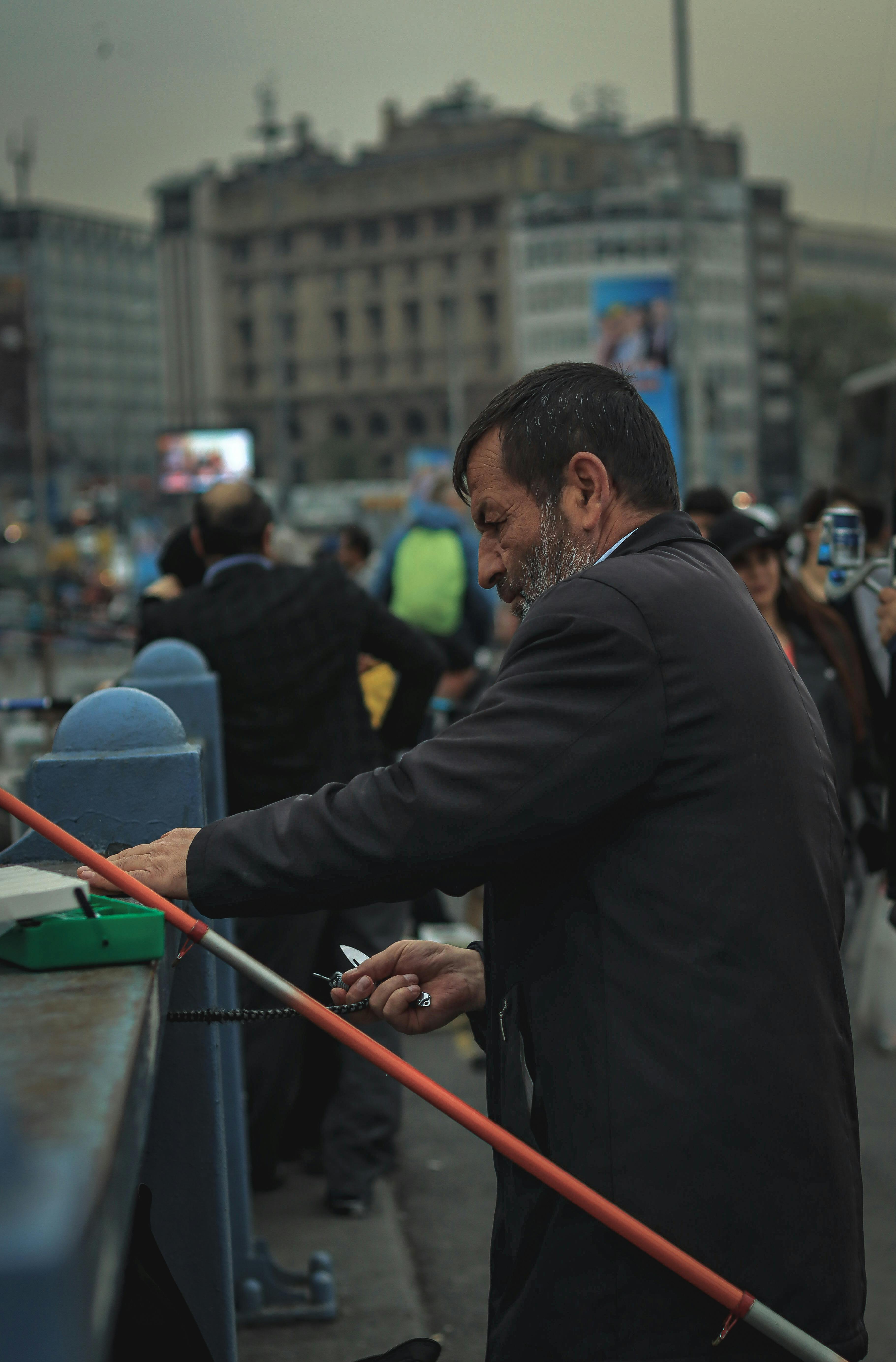 A Fisherman on a Crowded Bridge in City · Free Stock Photo