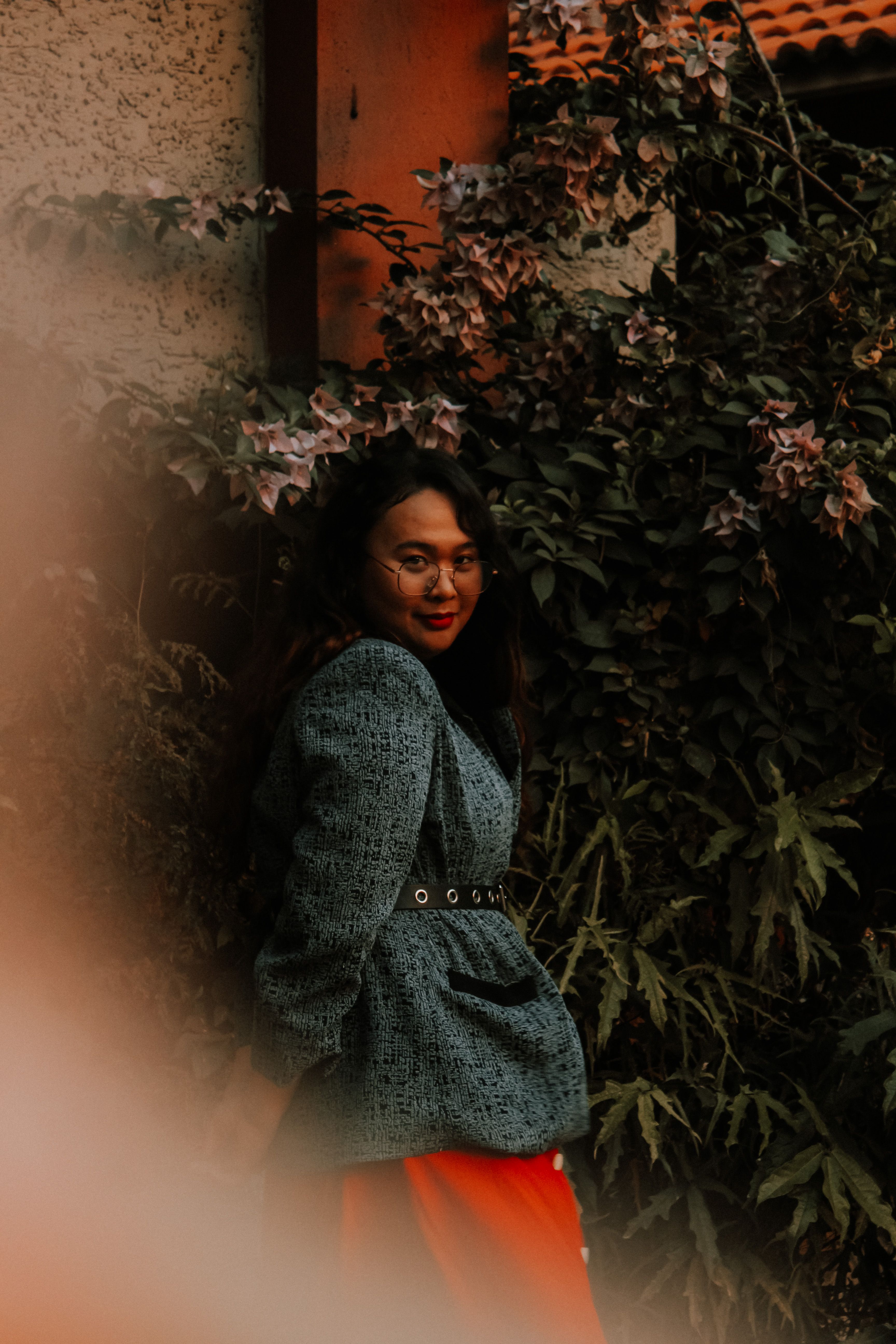 Woman Posing by Bush near Wall · Free Stock Photo