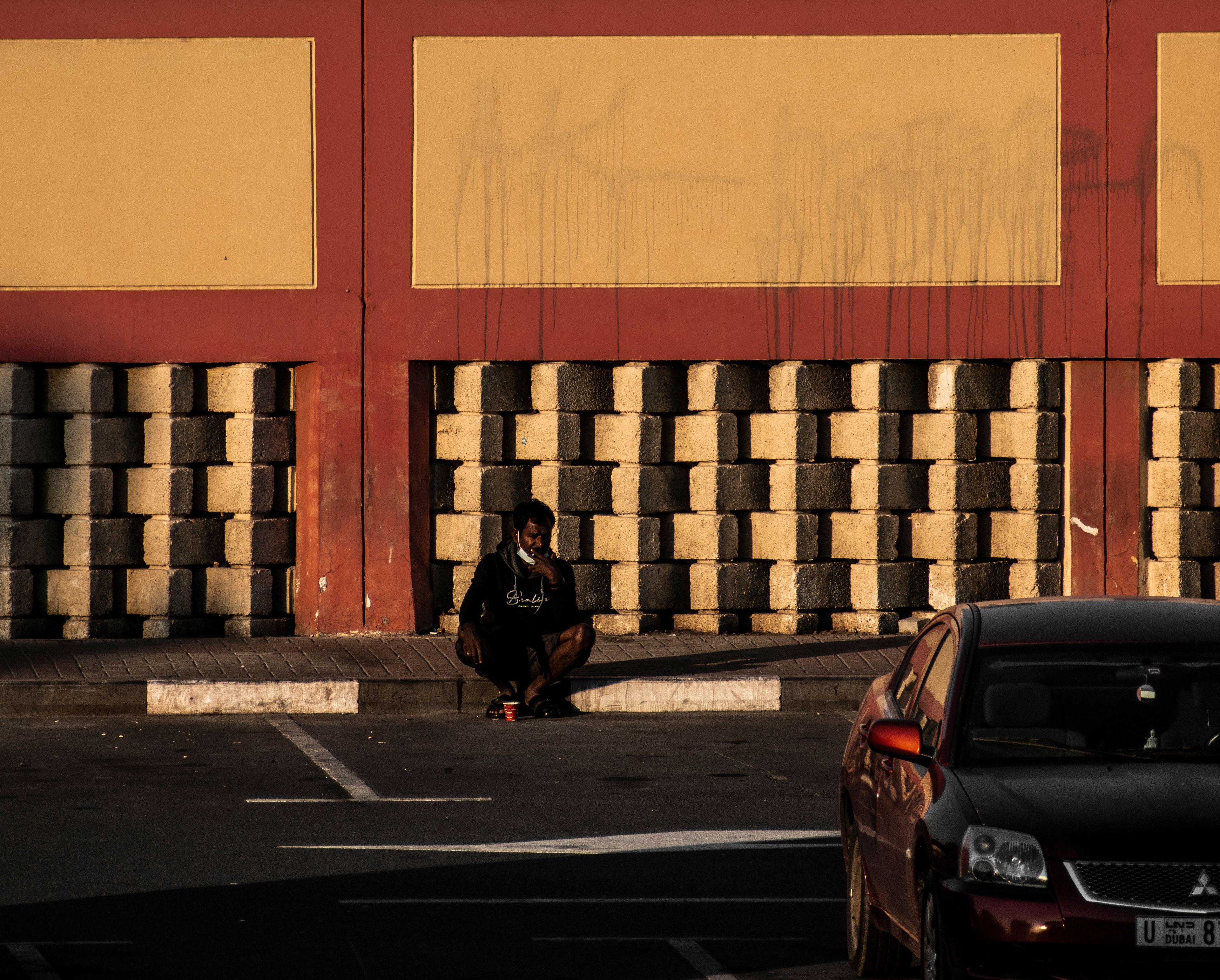 Man Sitting near Car at Parking Lot · Free Stock Photo