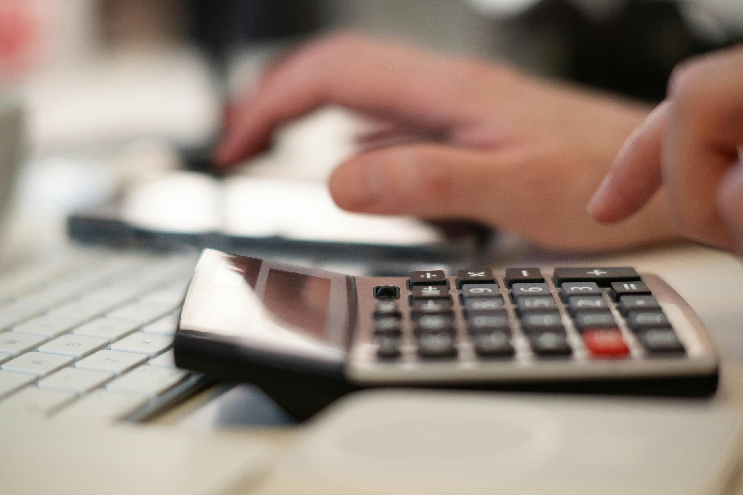 Woman Using a Calculator While Sitting In Front of a Laptop · Free ...