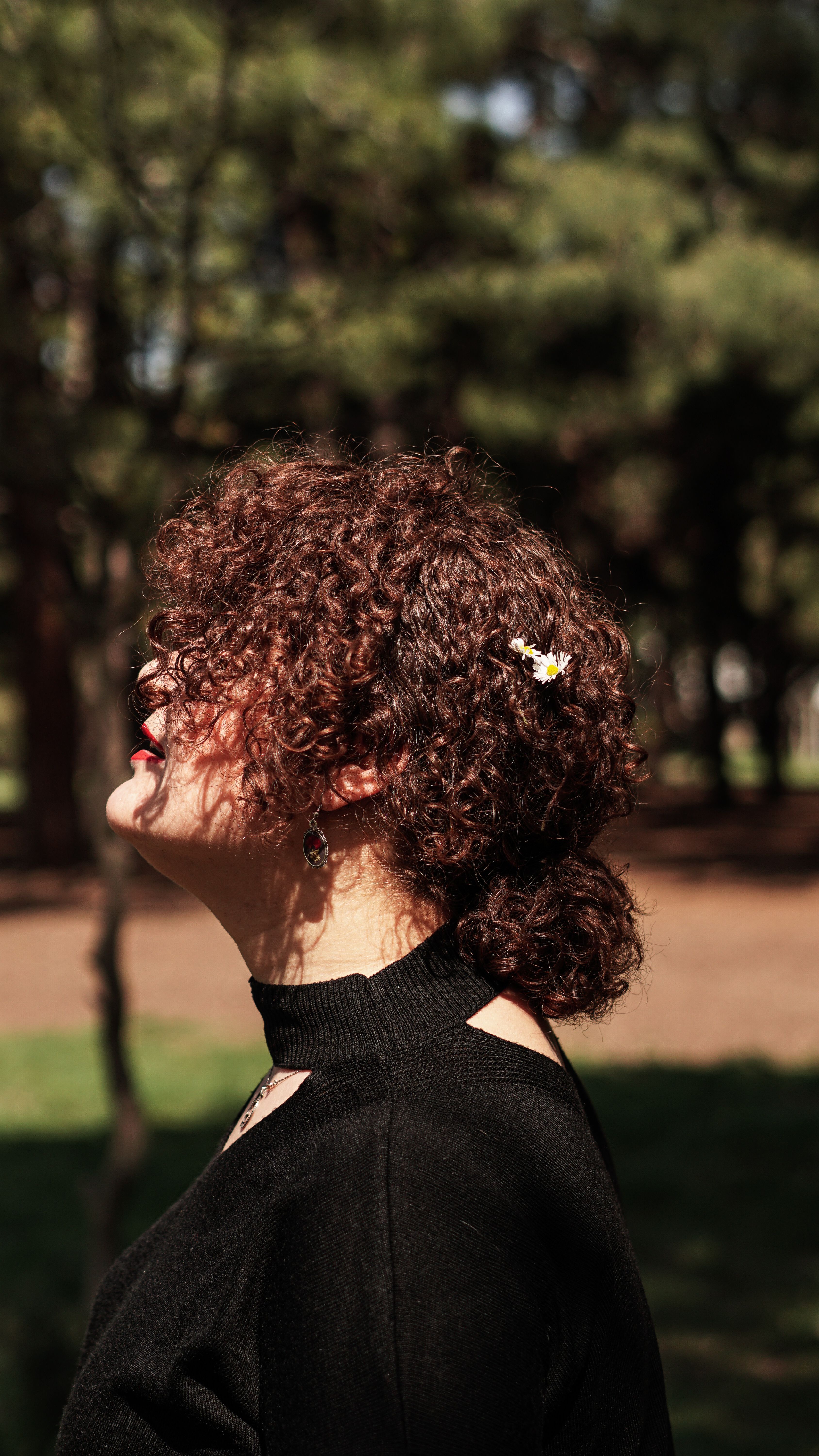 A woman with curly hair and a flower in her hair · Free Stock Photo