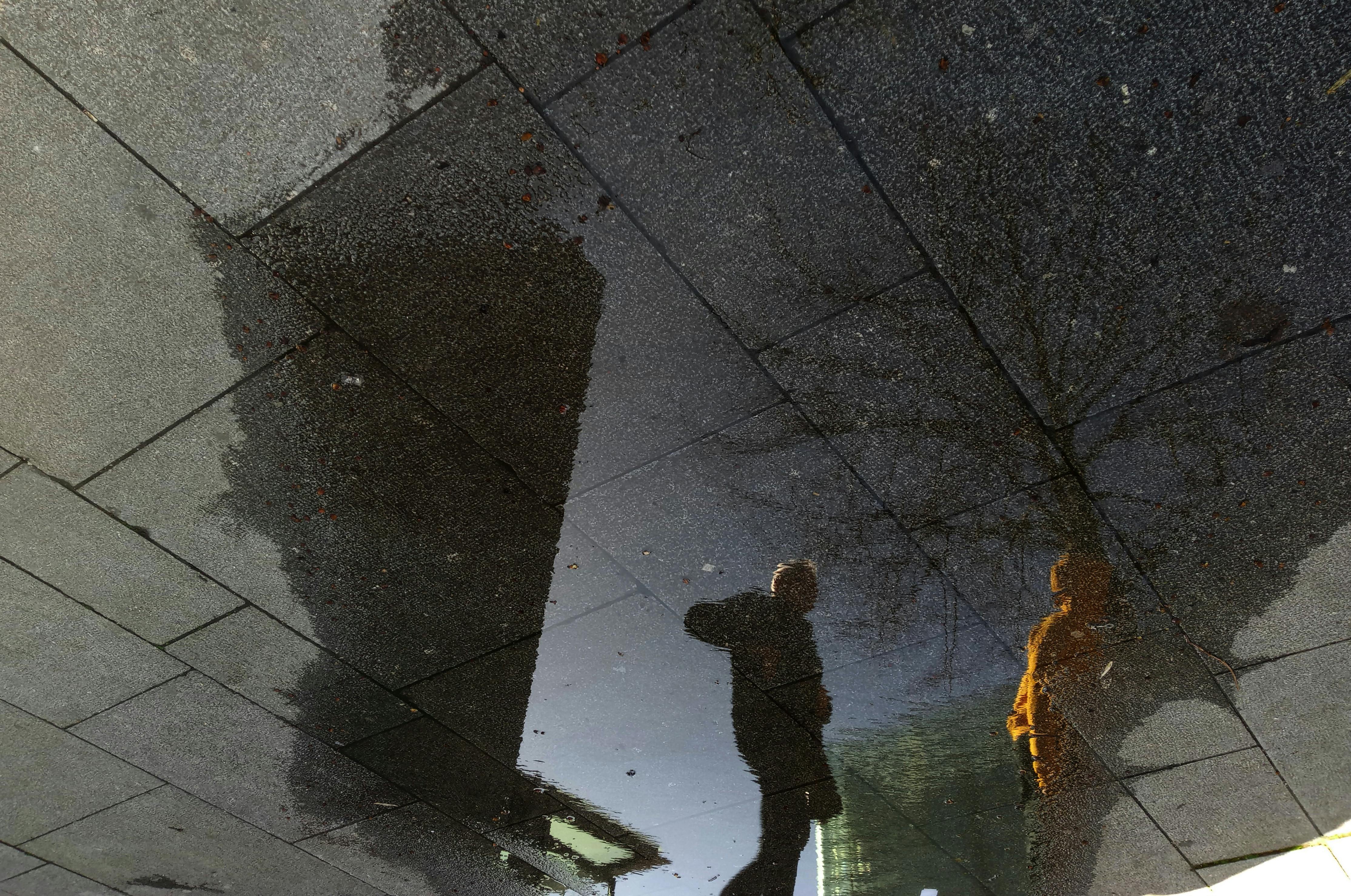 Upside Down Reflection of a Person in a Puddle on the Pavement · Free ...