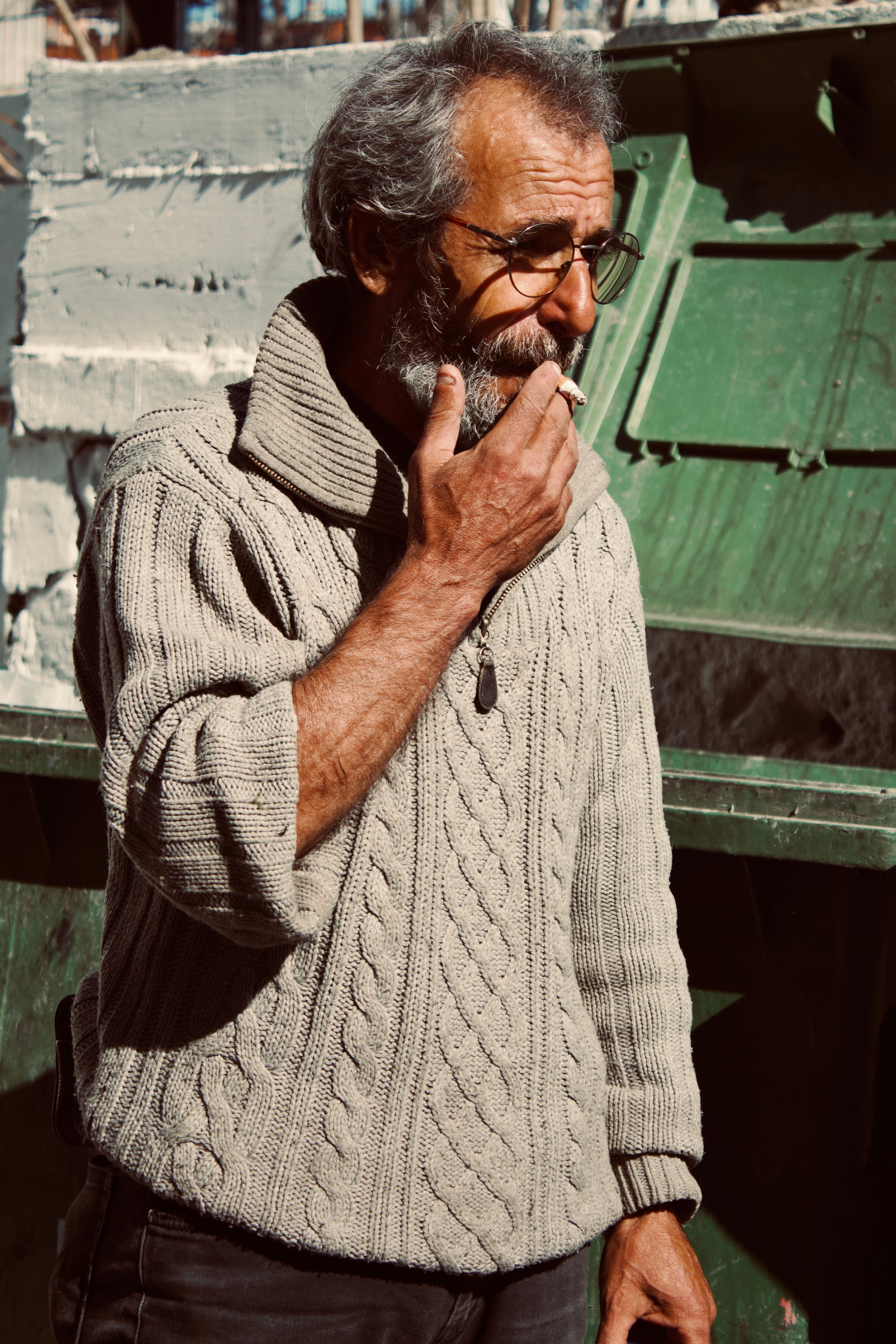 Elderly Man Sitting on a Field Smoking a Cigarette · Free Stock Photo