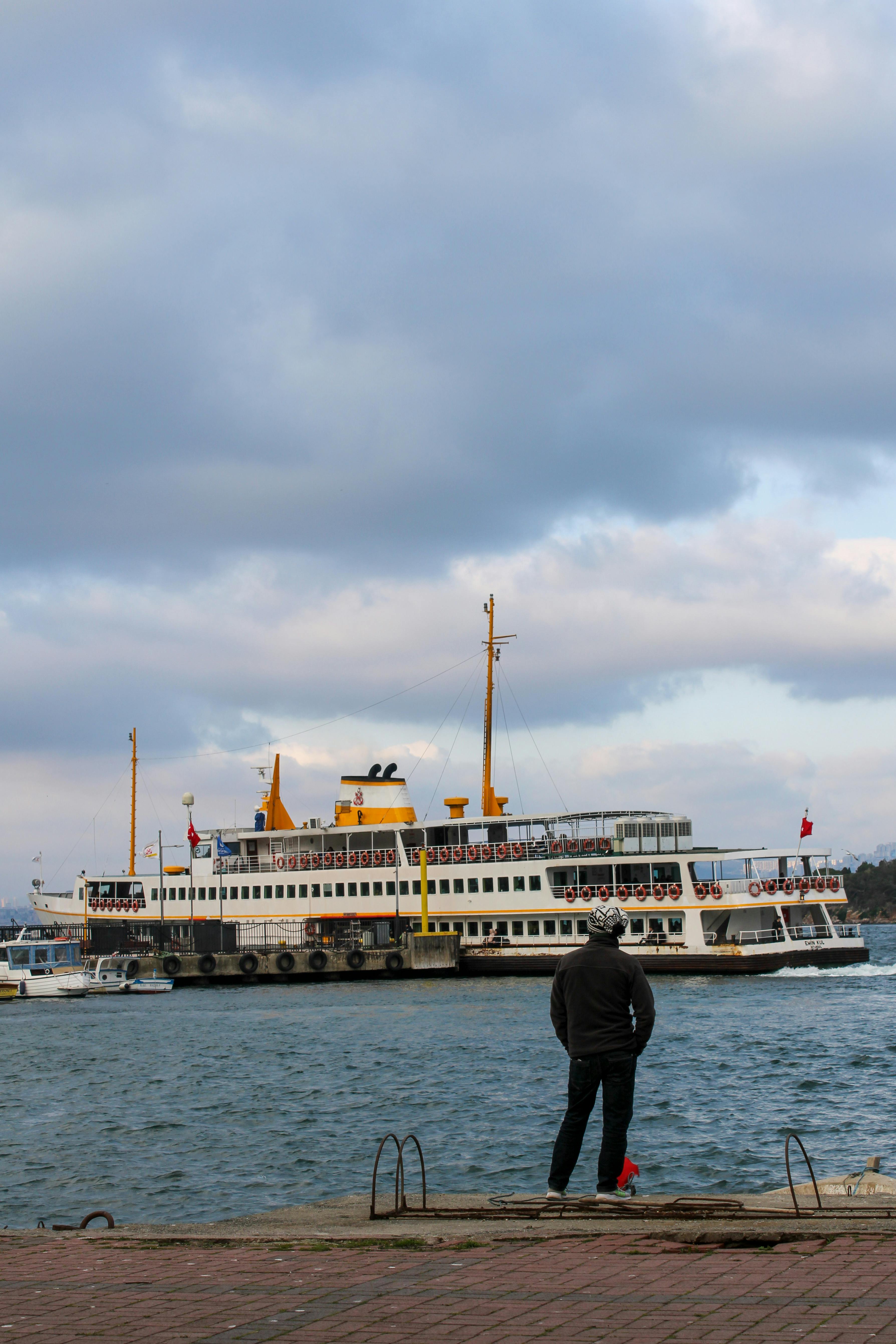 Man Standing on Shore with Ferry behind · Free Stock Photo