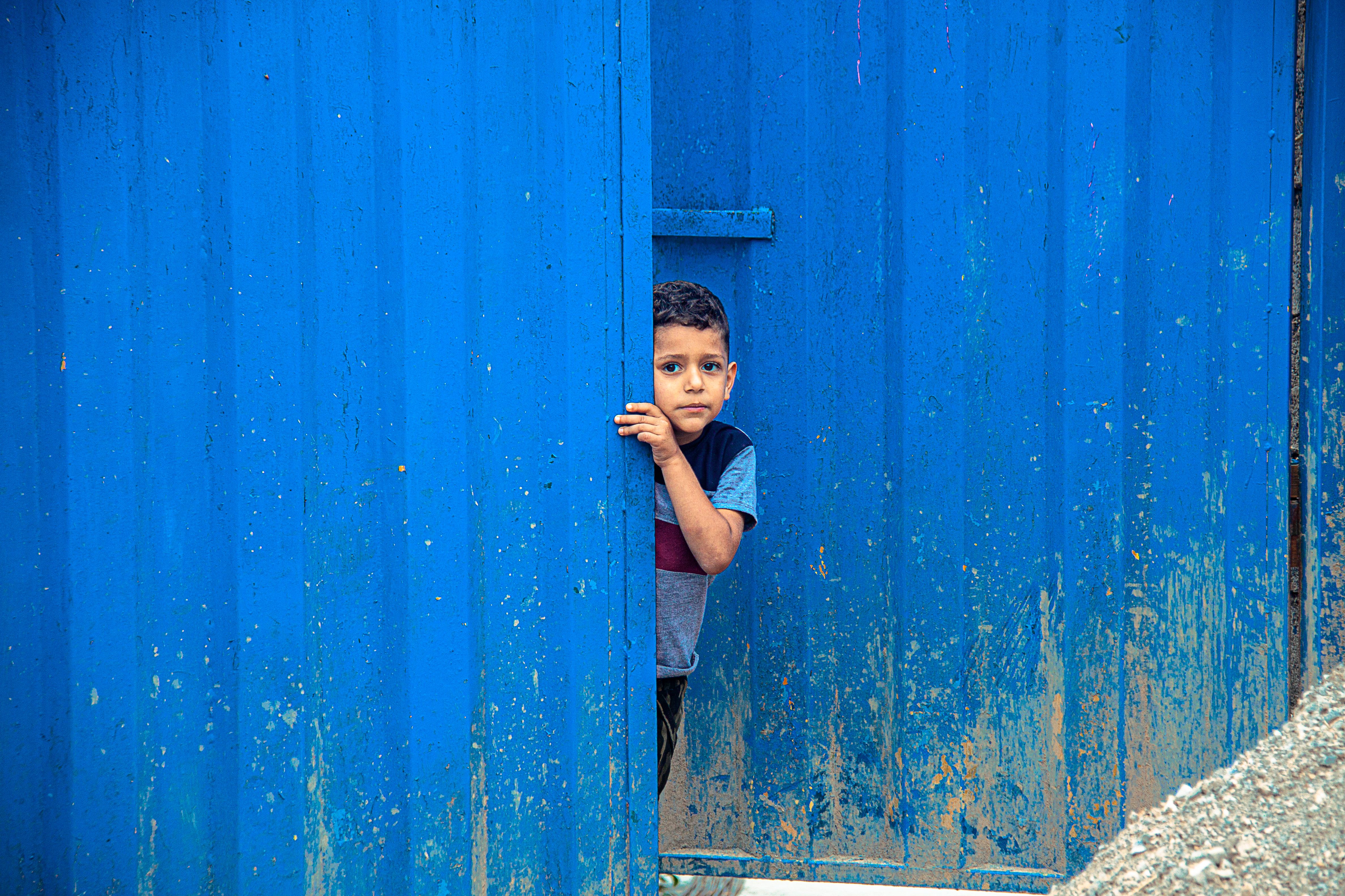 Little Boy Looking behind Blue Gates · Free Stock Photo