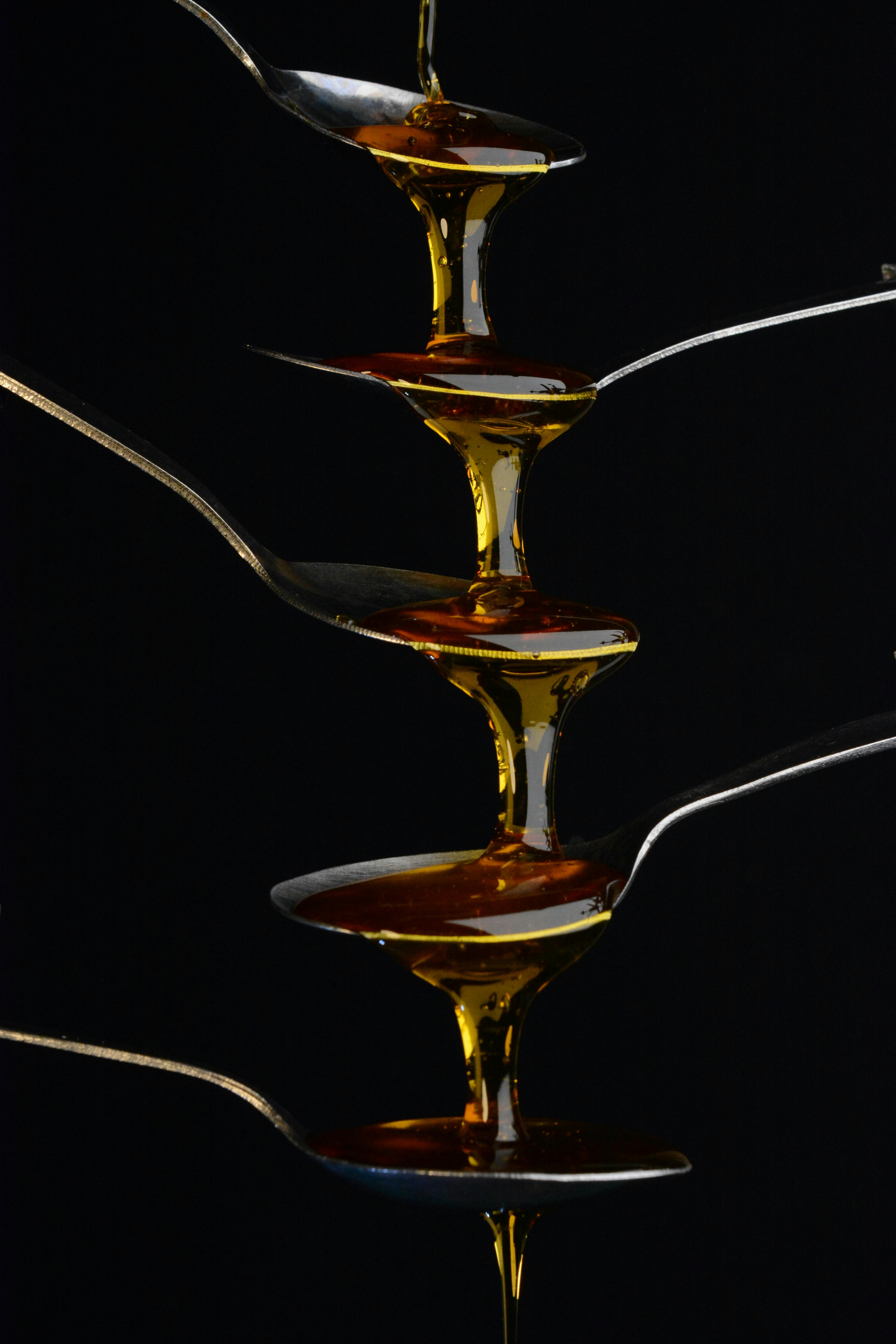 Honey Pouring on Spoons on Black Background · Free Stock Photo