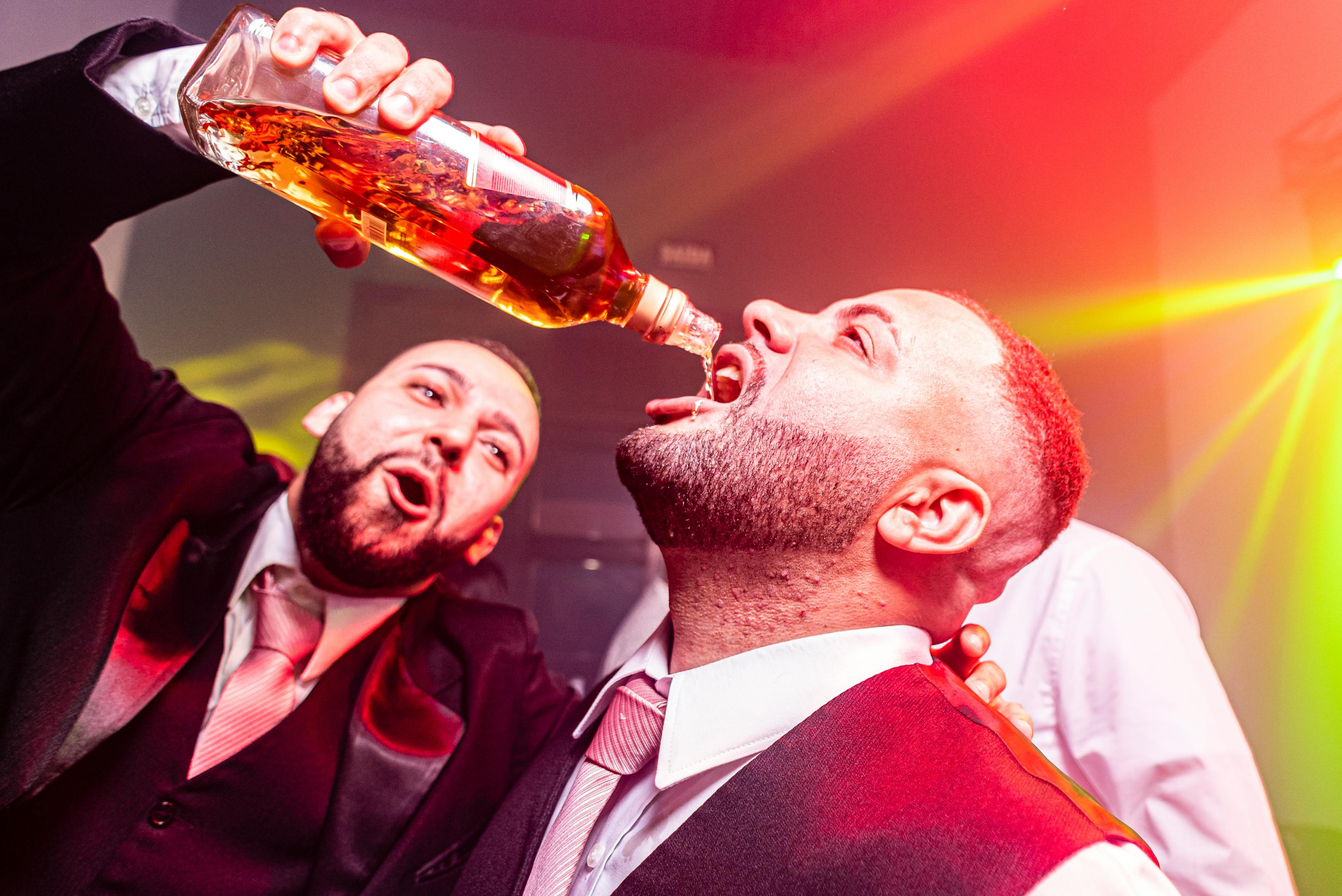 Man Pouring Alcohol to other Man Mouth · Free Stock Photo