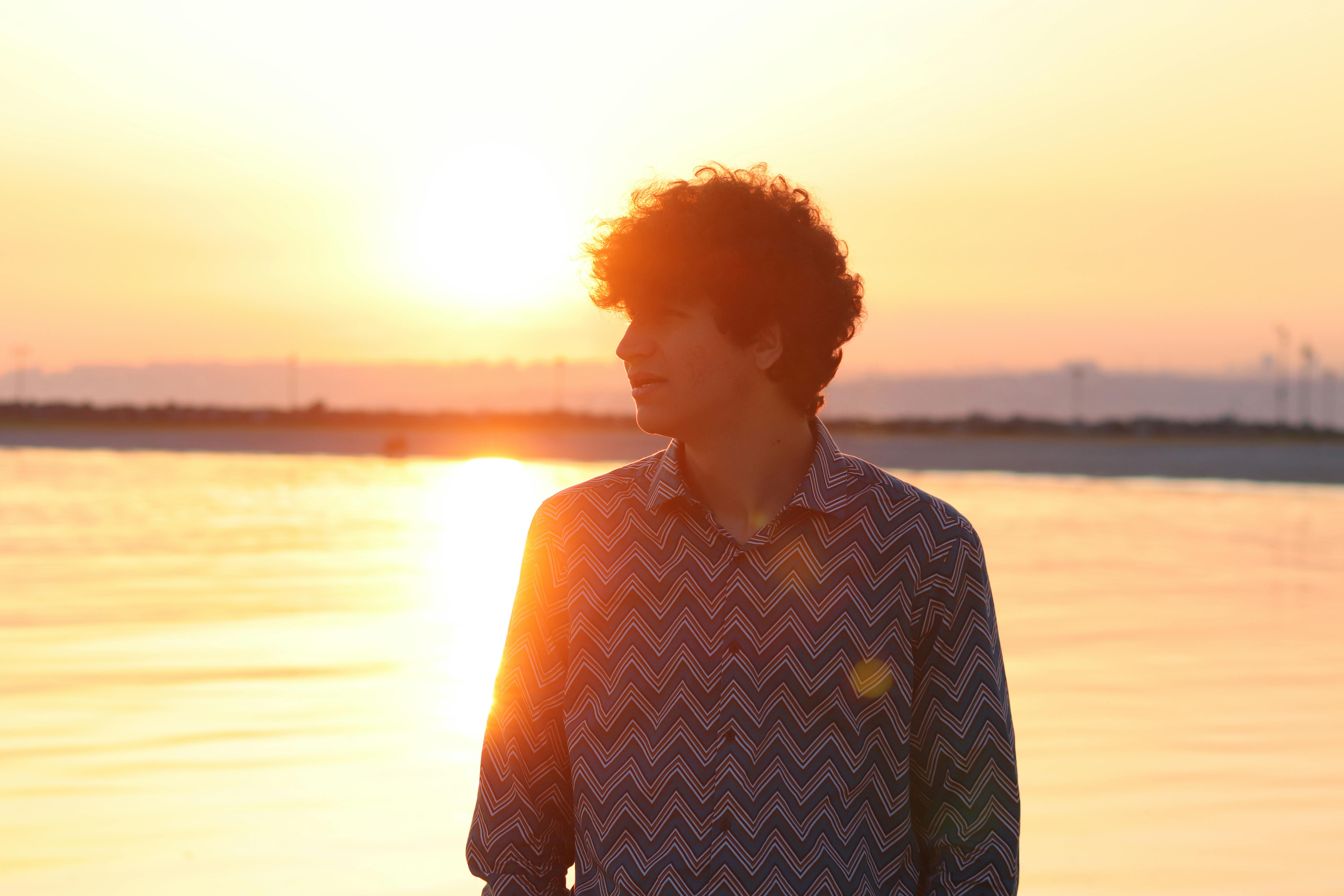 Backlit Young Man by the Sea at Sunset · Free Stock Photo