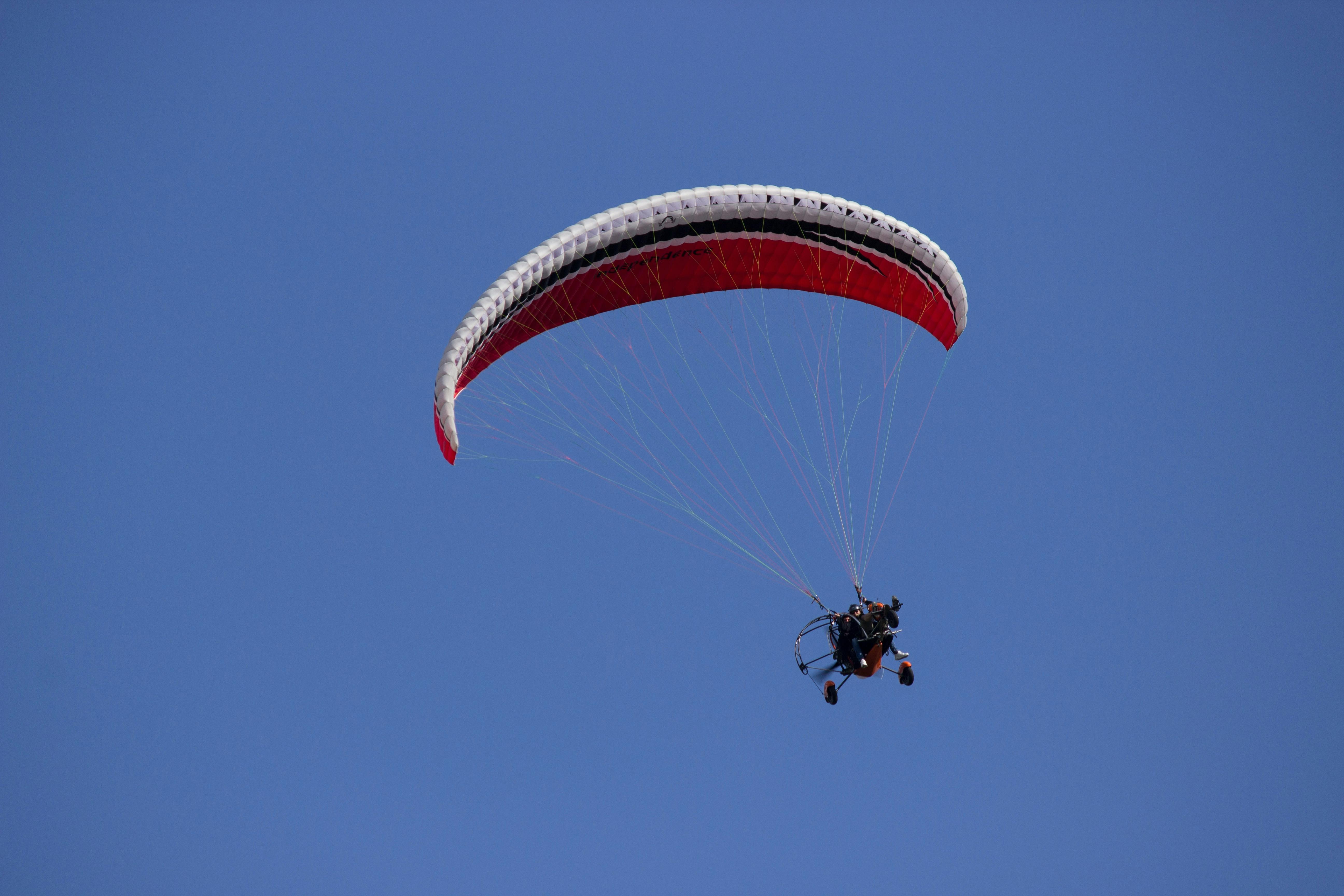 Person in Parachute Gliding Above Mountains · Free Stock Photo