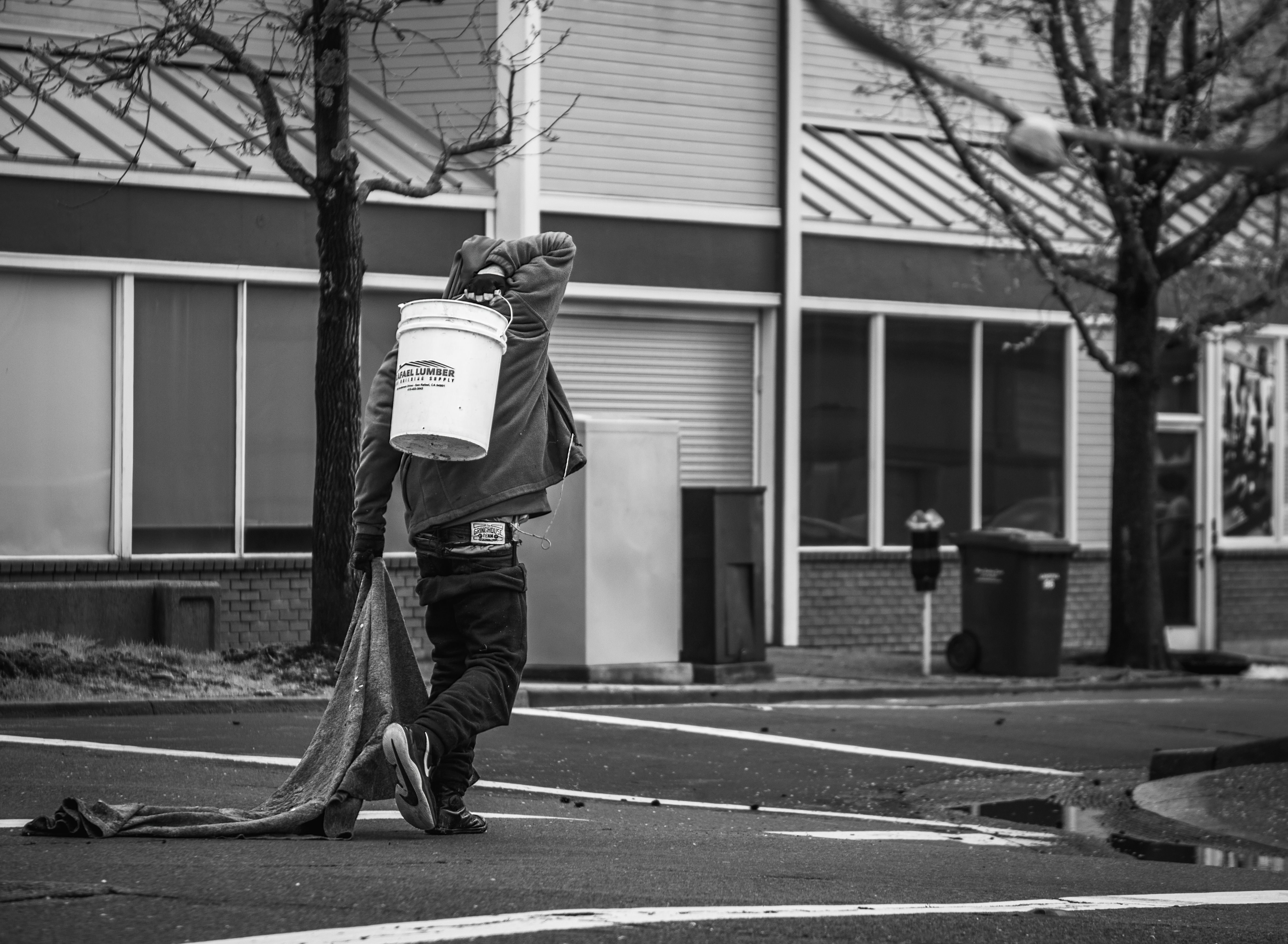 Man Carrying a Bucket and Fabric on a Street in City · Free Stock Photo
