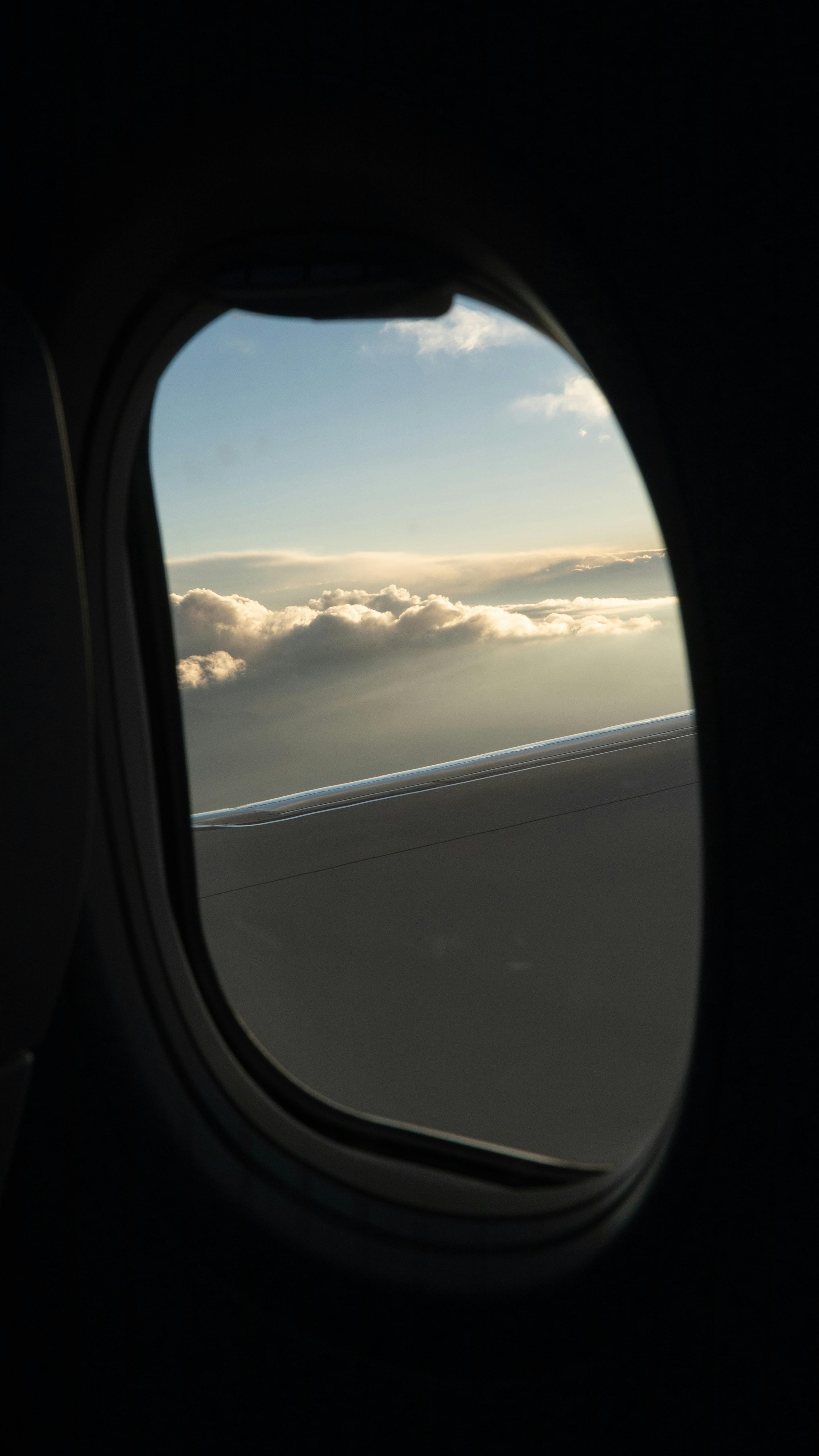 Clouds and Airplane Wing behind Window · Free Stock Photo