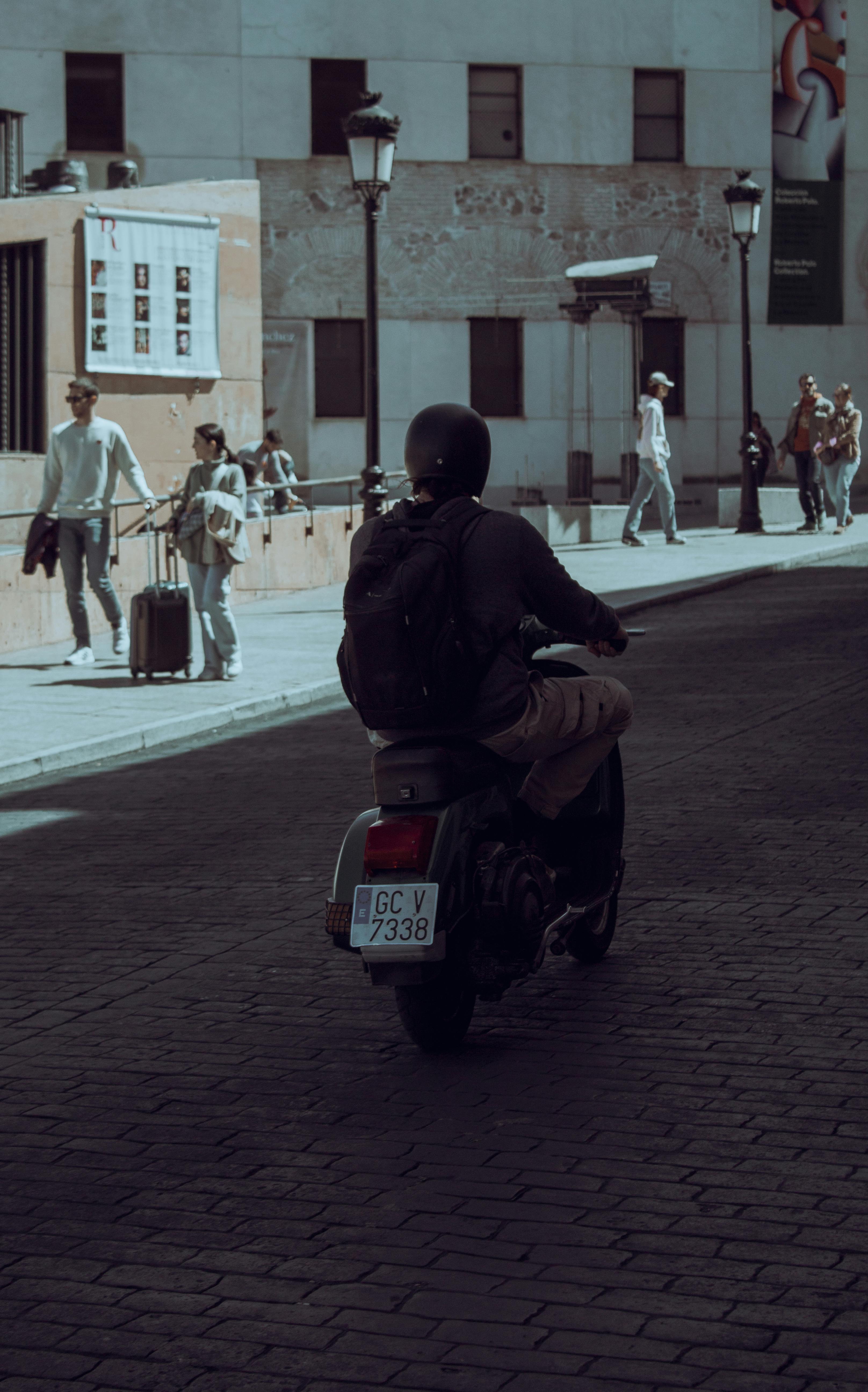 Person Riding Scooter on Street in Shadow · Free Stock Photo