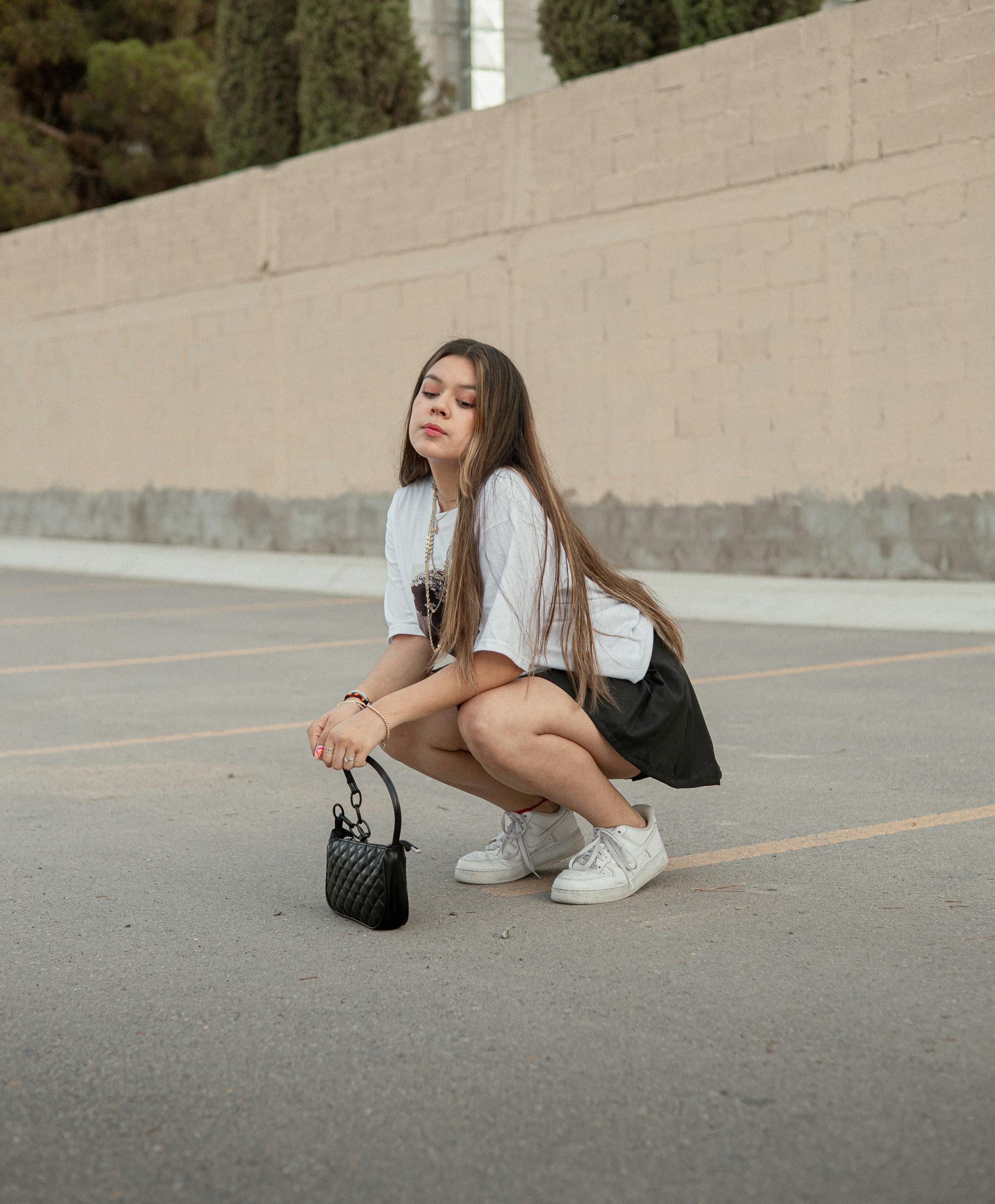 Woman in T-shirt Squatting and Posing on Parking Lot · Free Stock Photo