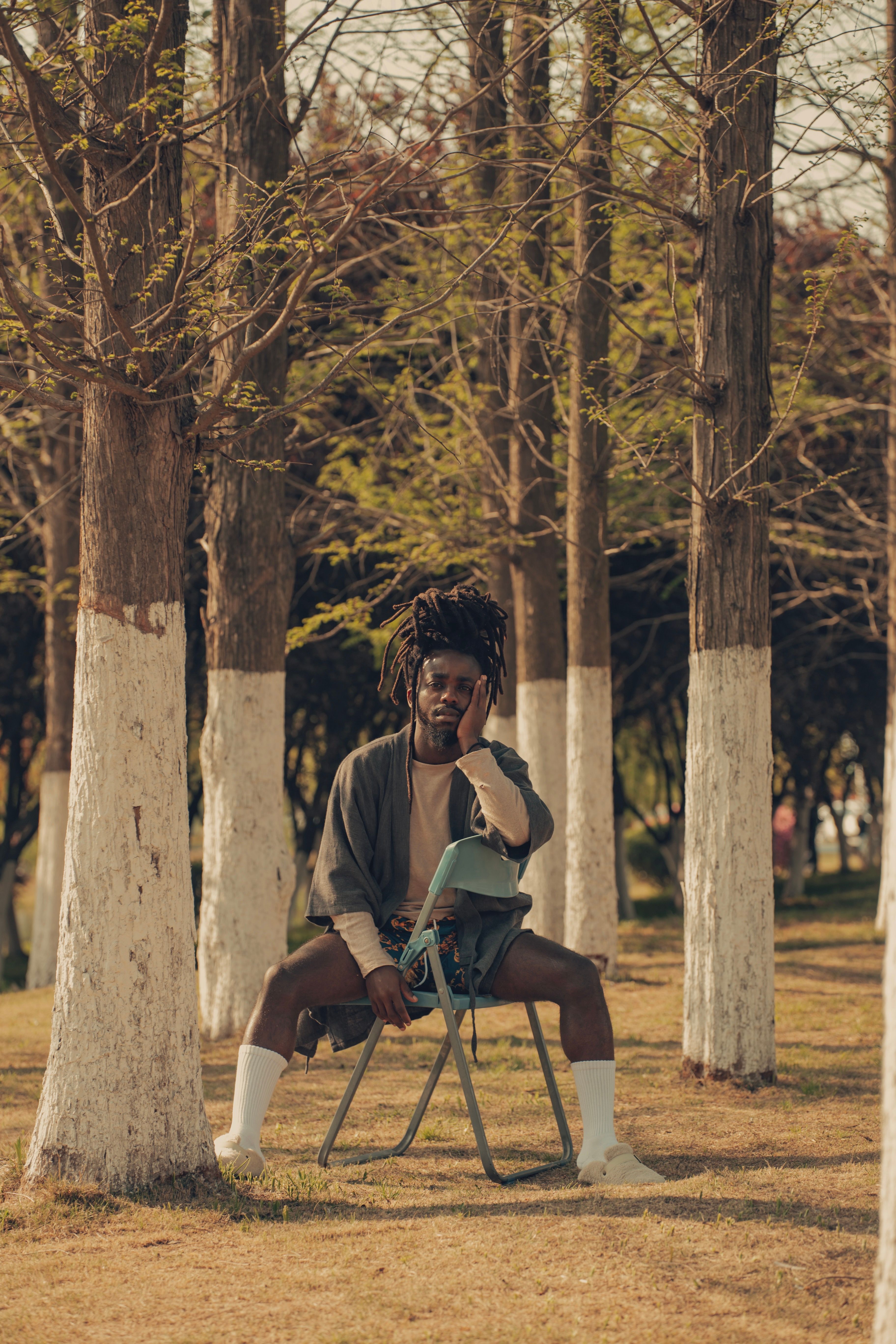 Photo of a Young Man with Dreadlocks Sitting on a Chair Between Trees ...