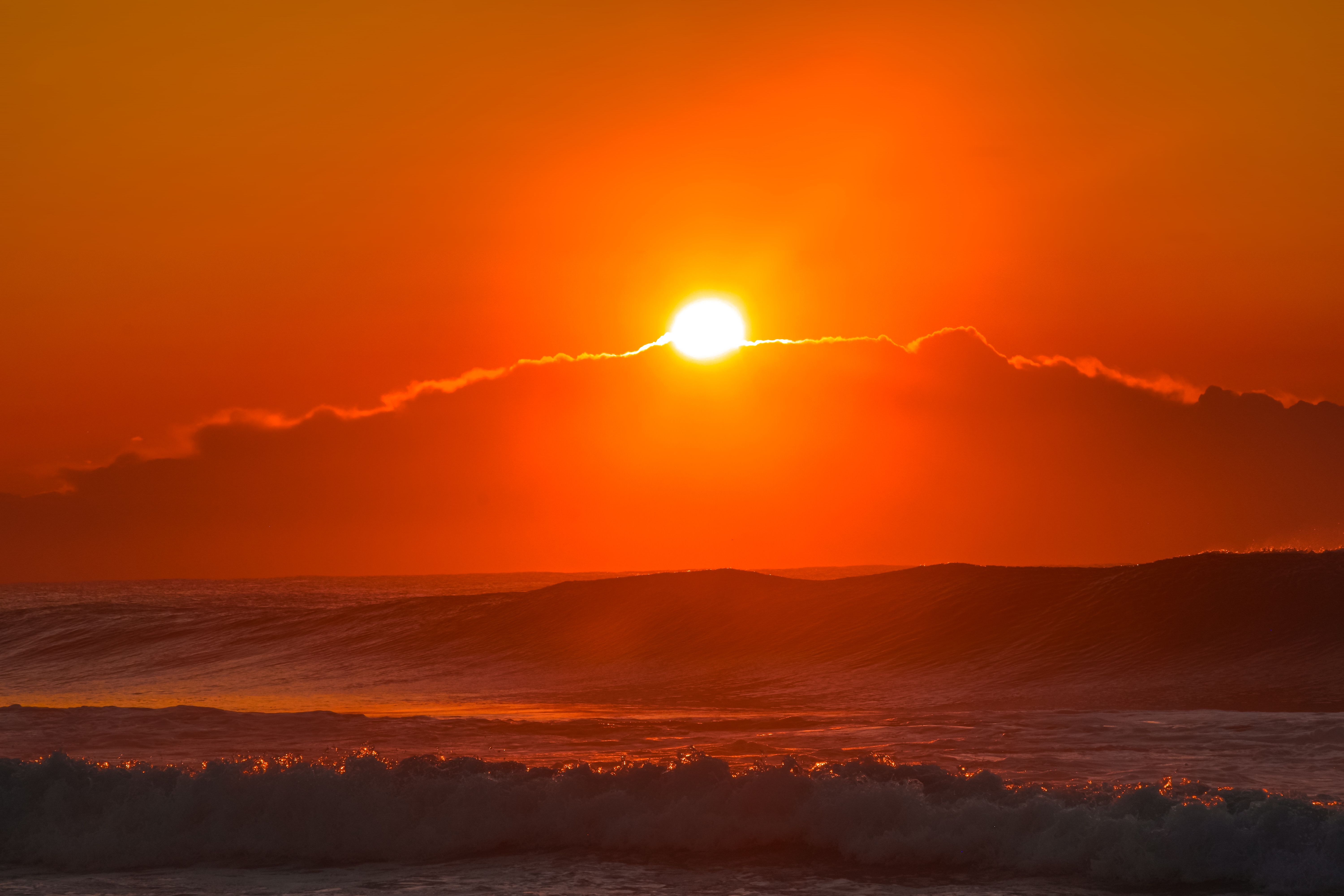 A sunset over the ocean with a bright orange sky · Free Stock Photo